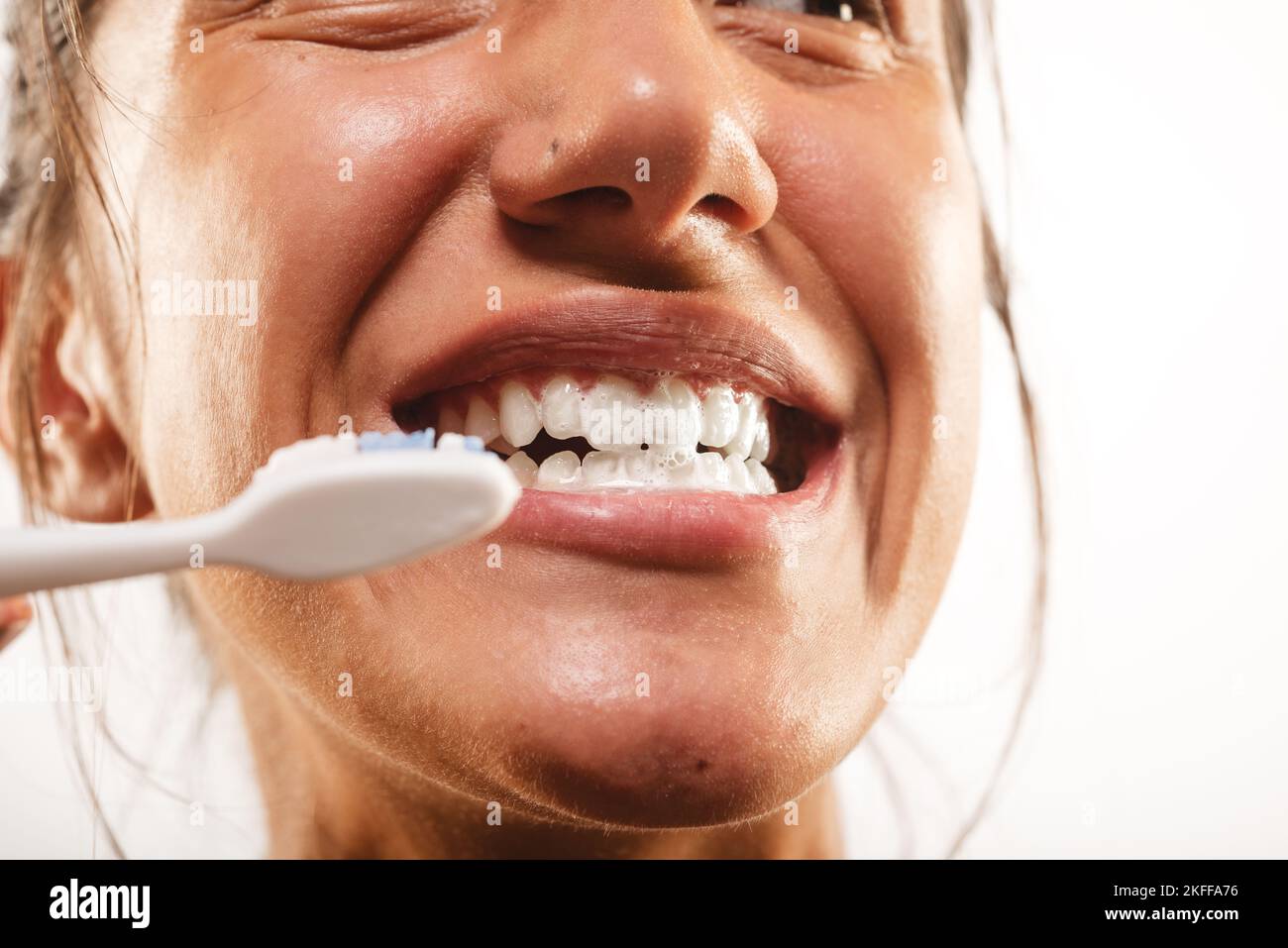 Close up of a girl washing her teeth at the studio on a white backround ...