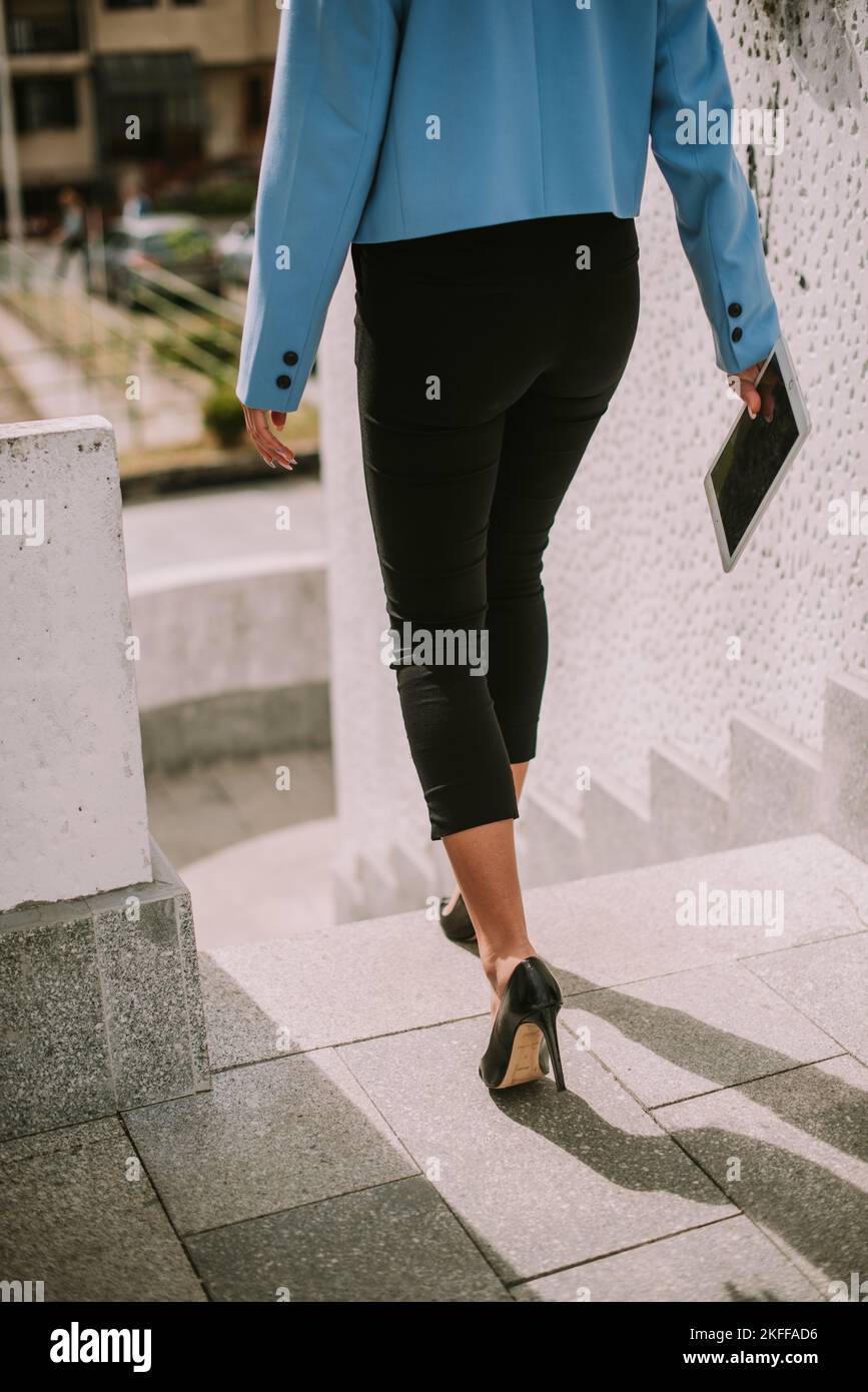 Business woman walking down the stairs while holding her tablet Stock ...