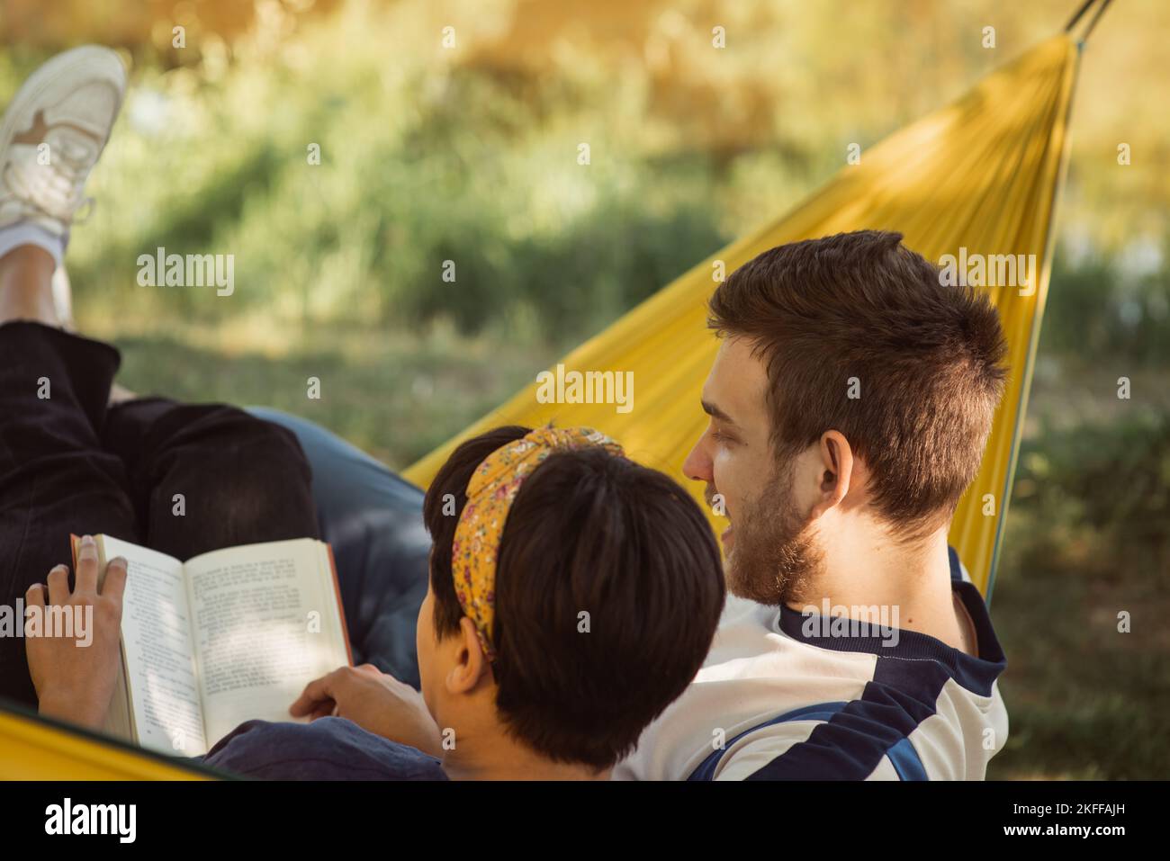 Close up of a beautiful couple reading a book together while sitting on ...