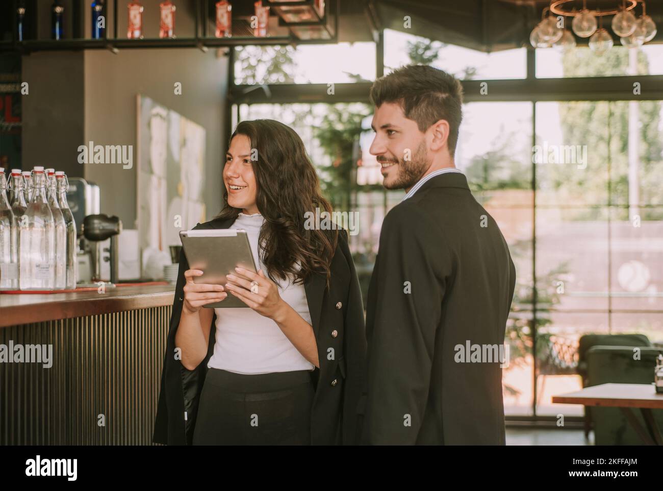 Business partners looking away while standing near the bar at the cafe ...