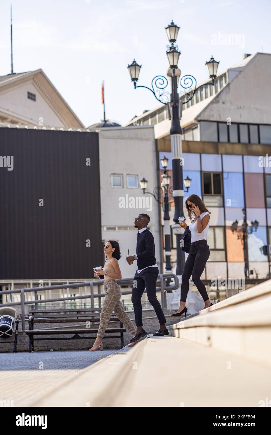 Three multiracial business partners are walking together and taking a ...