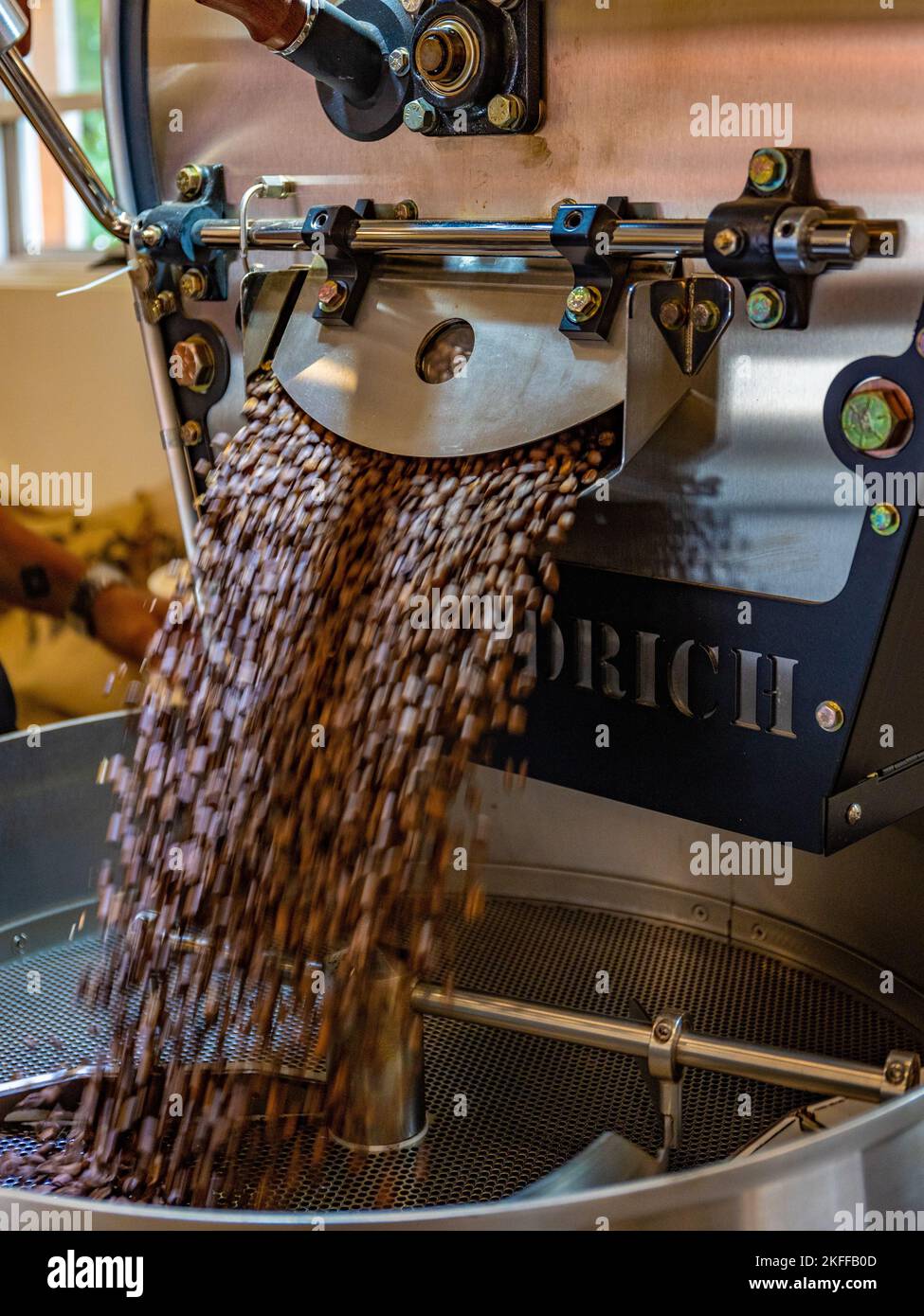 A vertical shot of a coffee beans roasting machine with a blurry ...
