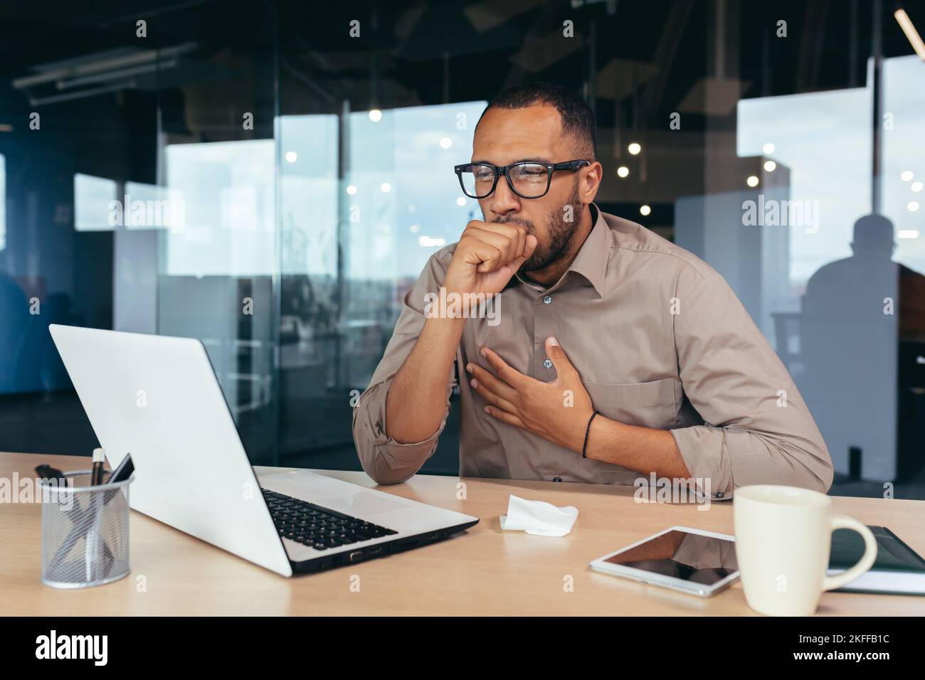 Businessman coughing at work in office, african american man in glasses ...