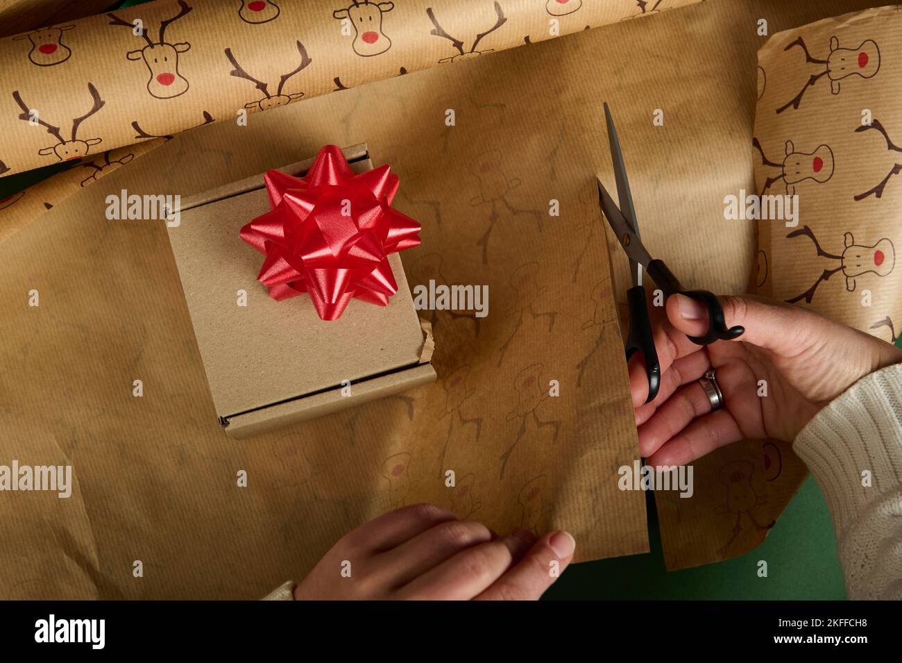Top view: Wrapping Christmas present in decorative paper with deer ...