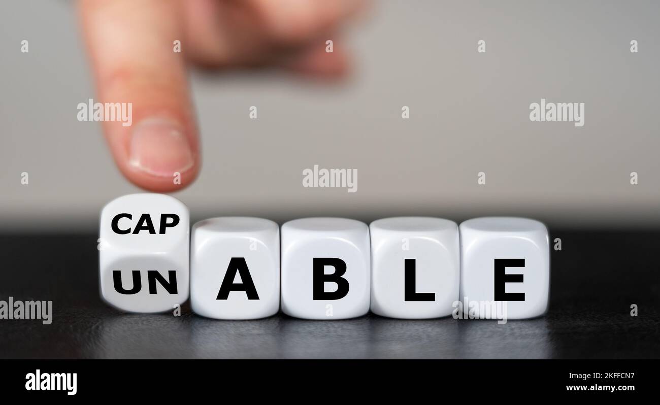 Hand turns dice and changes the word unable to capable Stock Photo - Alamy