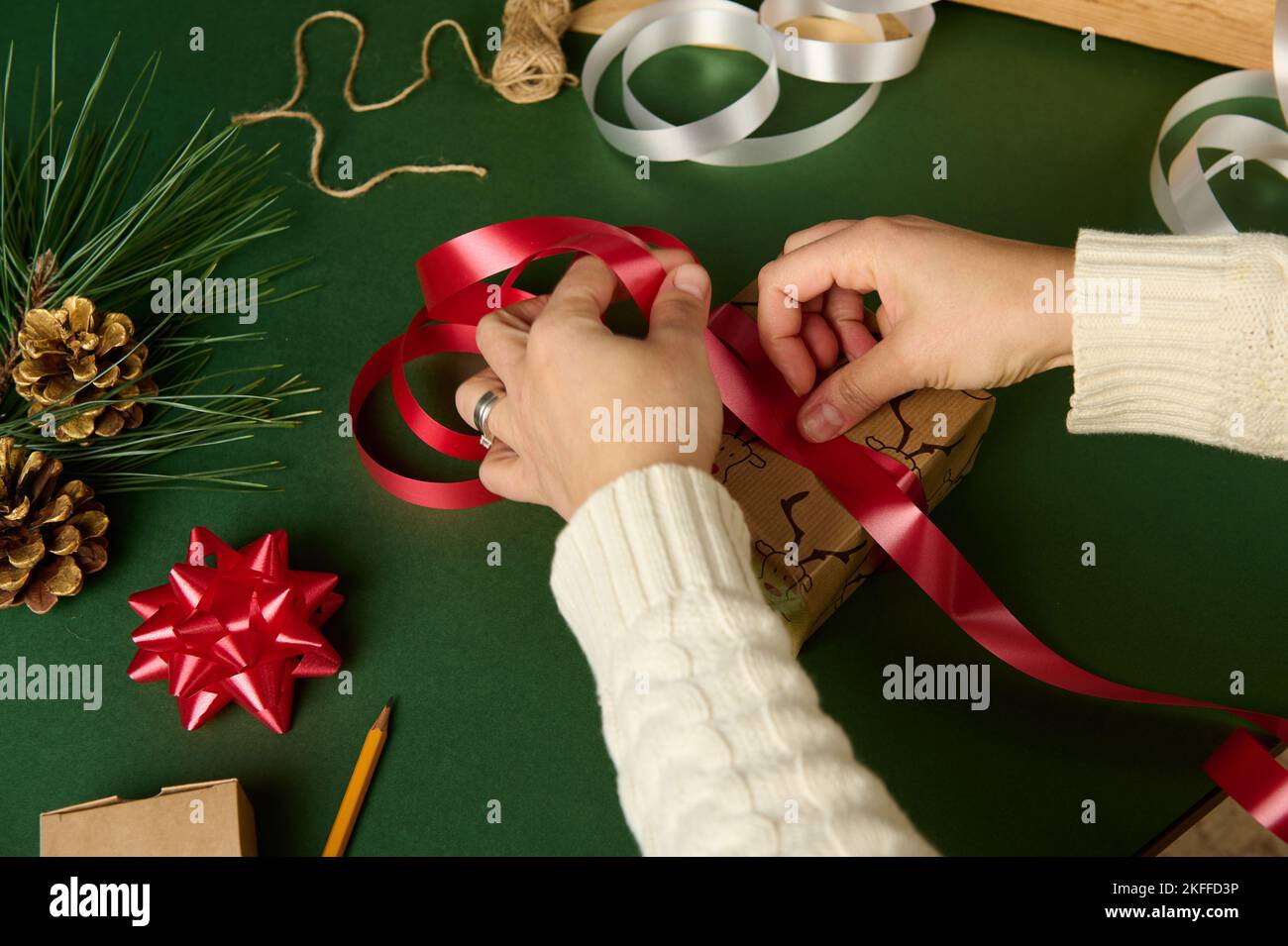 Overhead view of woman's hands tying up a christmas present with a ...