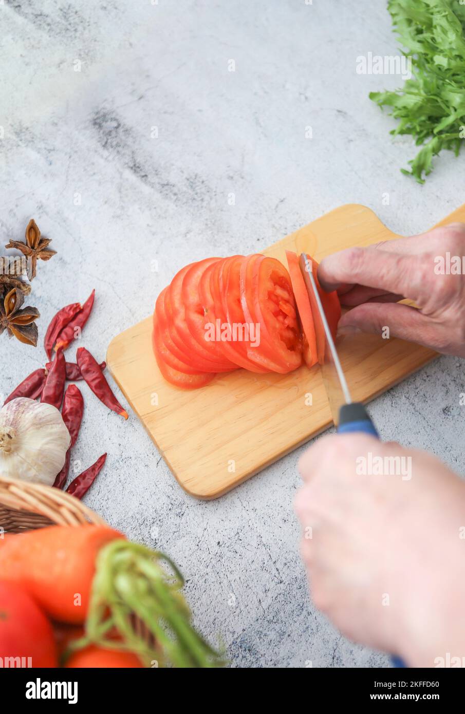 A Vertical shot of a chef slicing tomatoes on a wooden board Stock ...