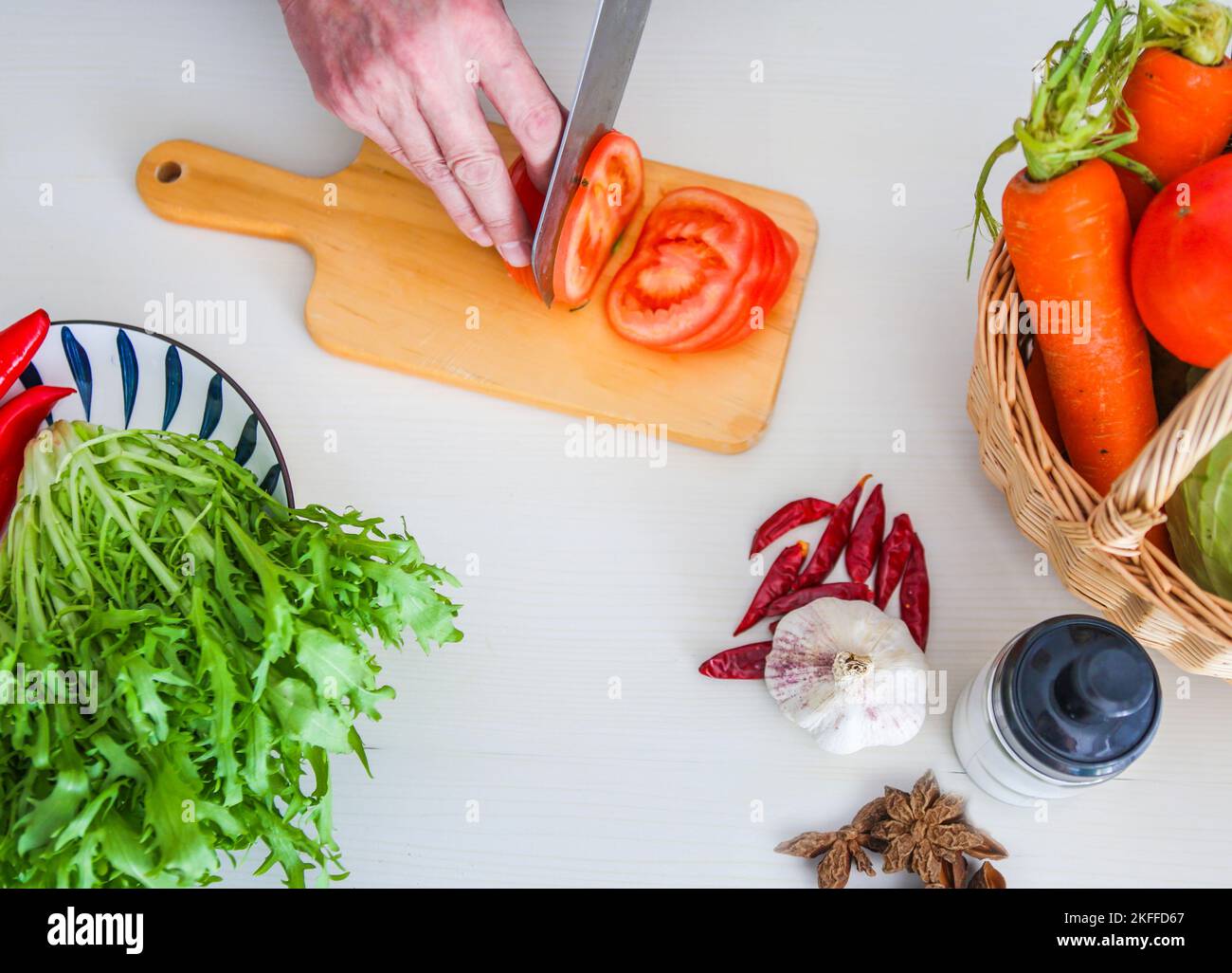 A top view of a chef slicing tomatoes on a wooden board Stock Photo - Alamy