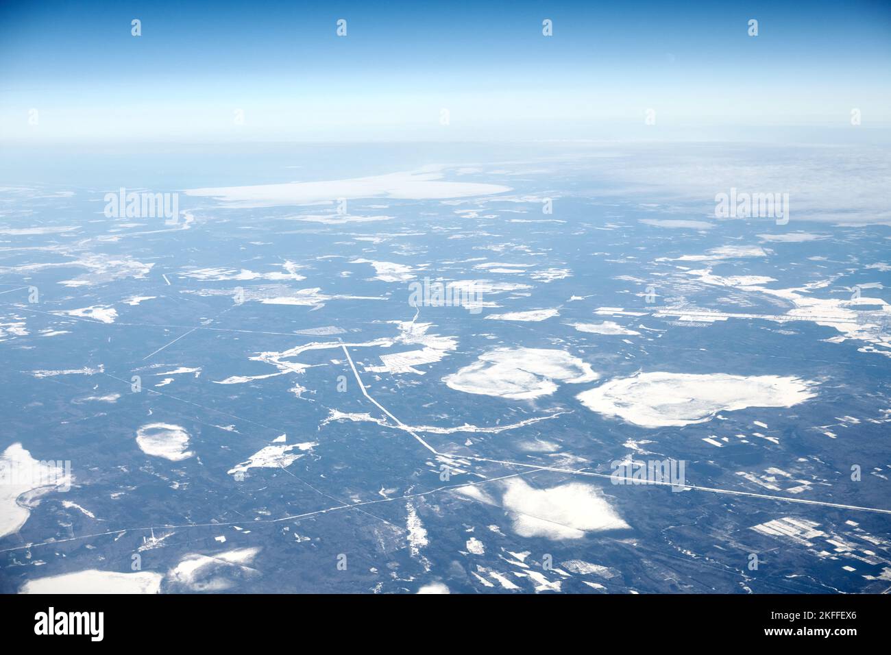 Aerial view from airplane window over clouds top to snow covered rivers ...