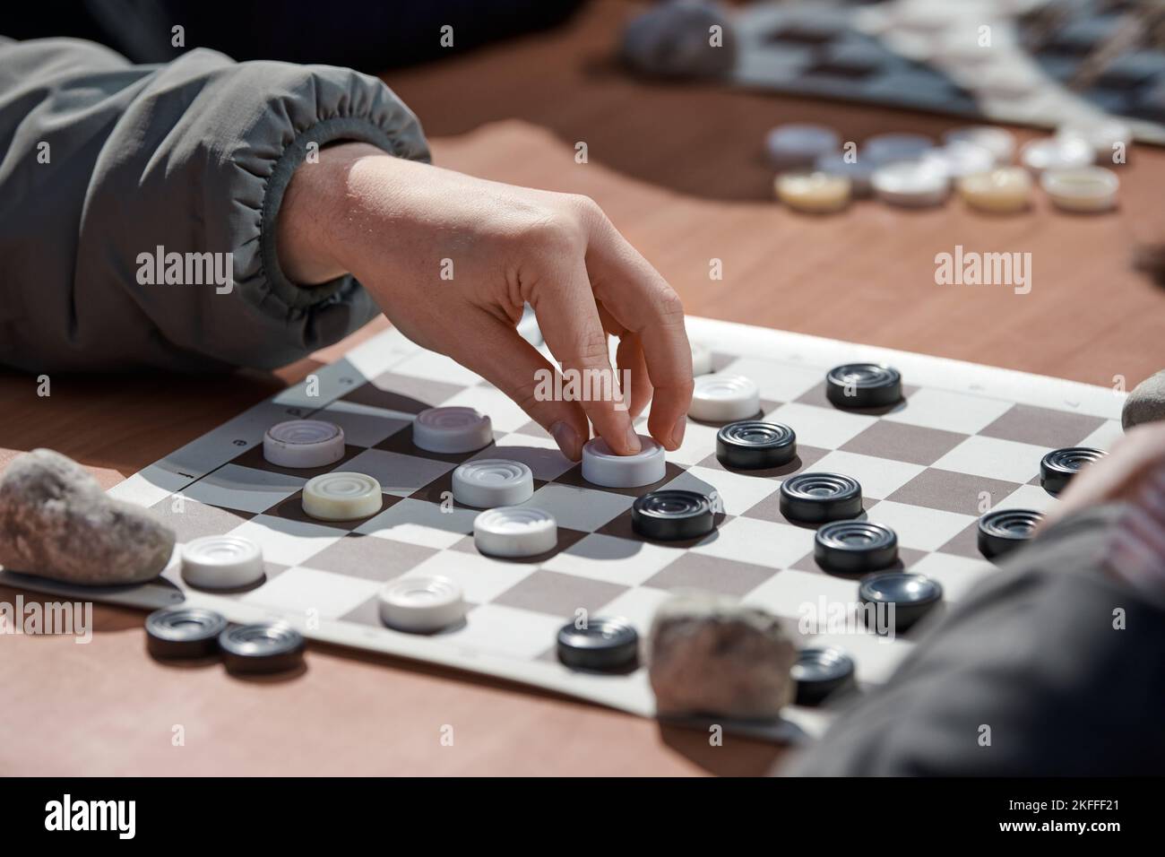 Outdoor draughts competition on paper checkerboard on table, close up ...