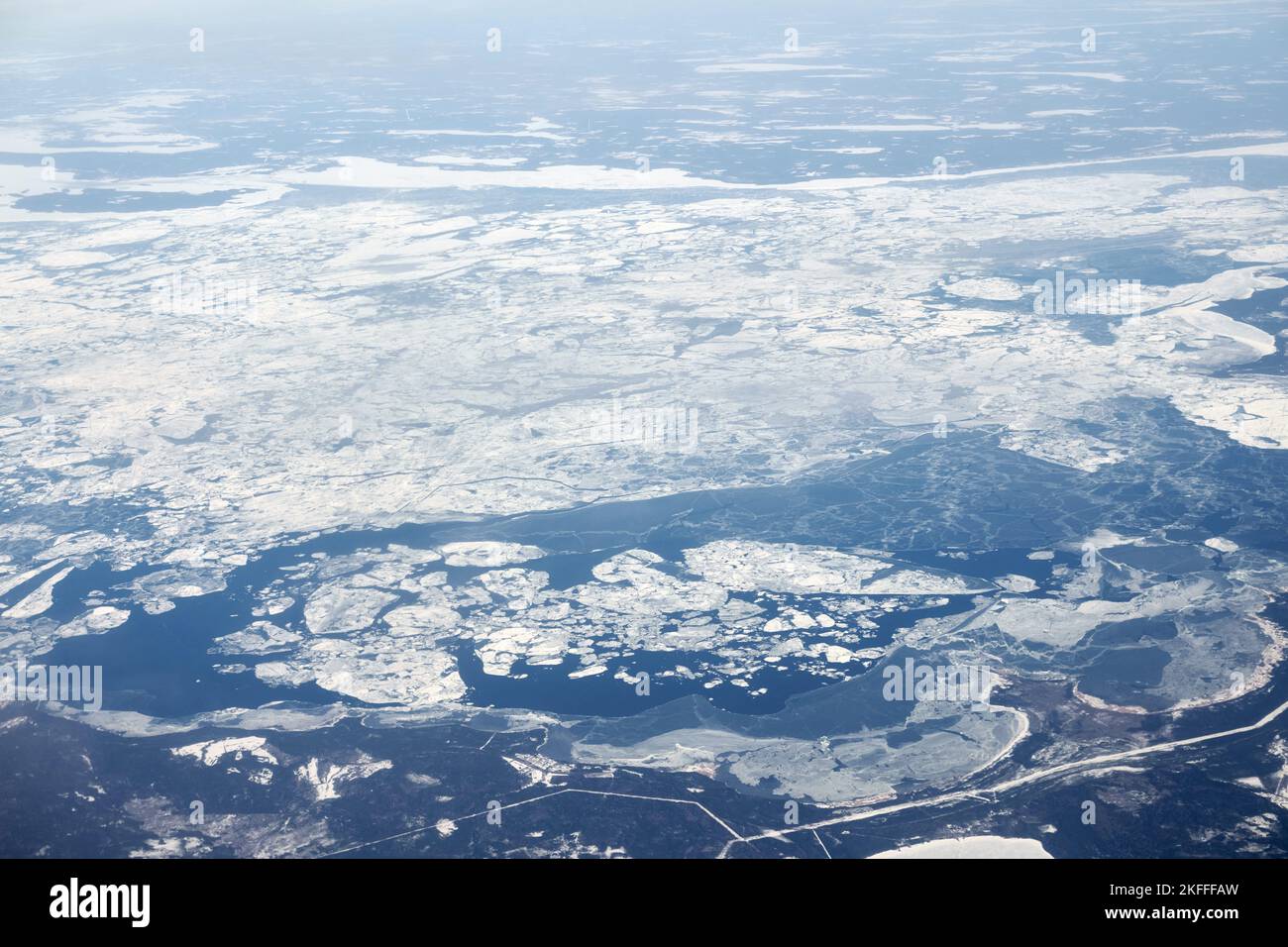 Aerial view from airplane window over clouds top to snow covered rivers ...