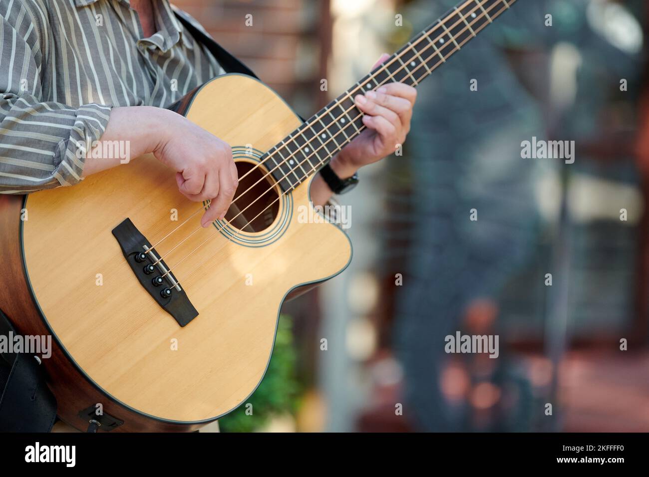 Man playing acoustic bass guitar at outdoor event, close up view to ...