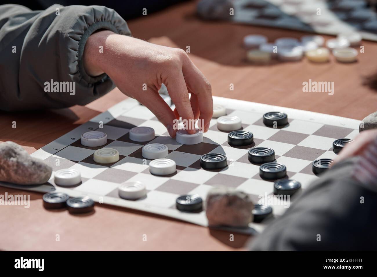 Outdoor checkers tournament on paper checkerboard on table, close up ...