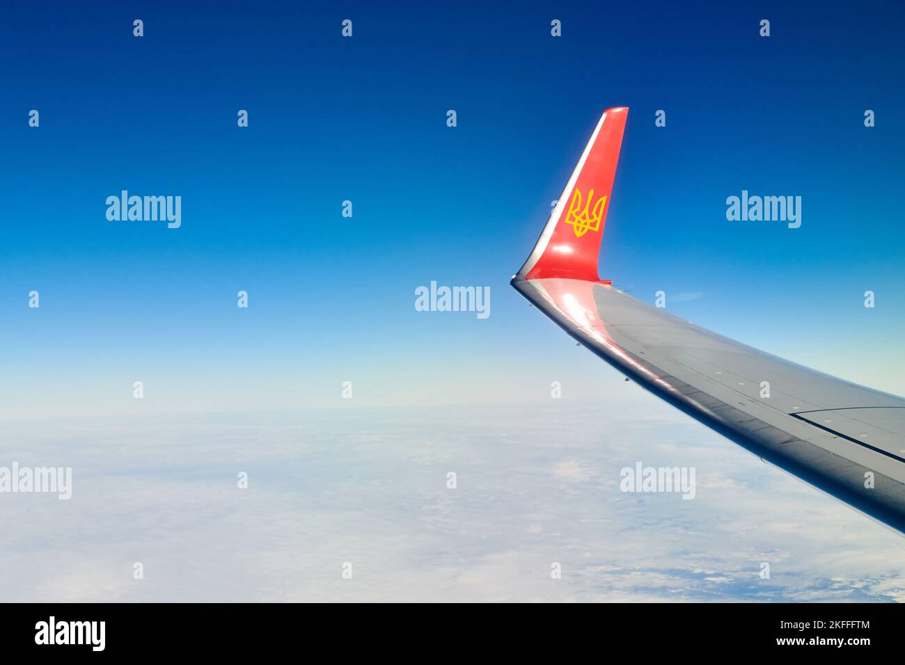 Airplane wing with coat of arms of Ukraine over clouds aerial top view ...