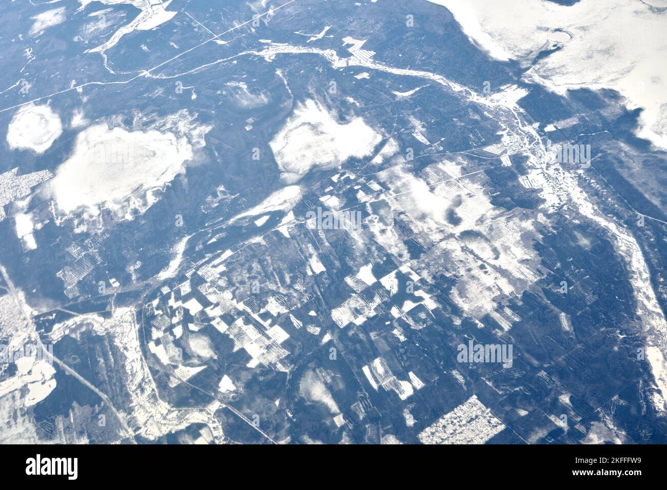 Aerial view from airplane window over clouds top to snow covered rivers ...