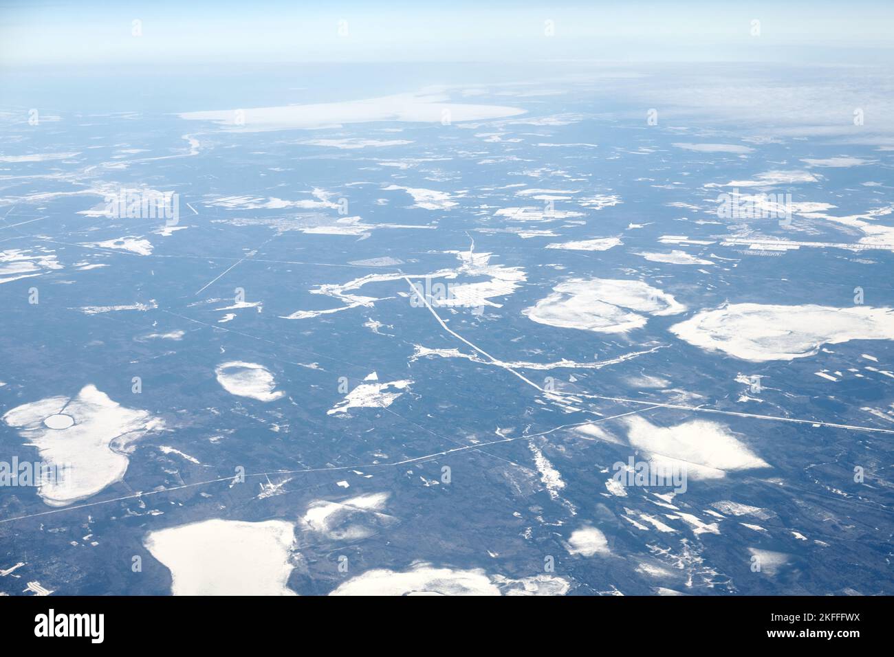 Aerial view from airplane window over clouds top to snow covered rivers ...