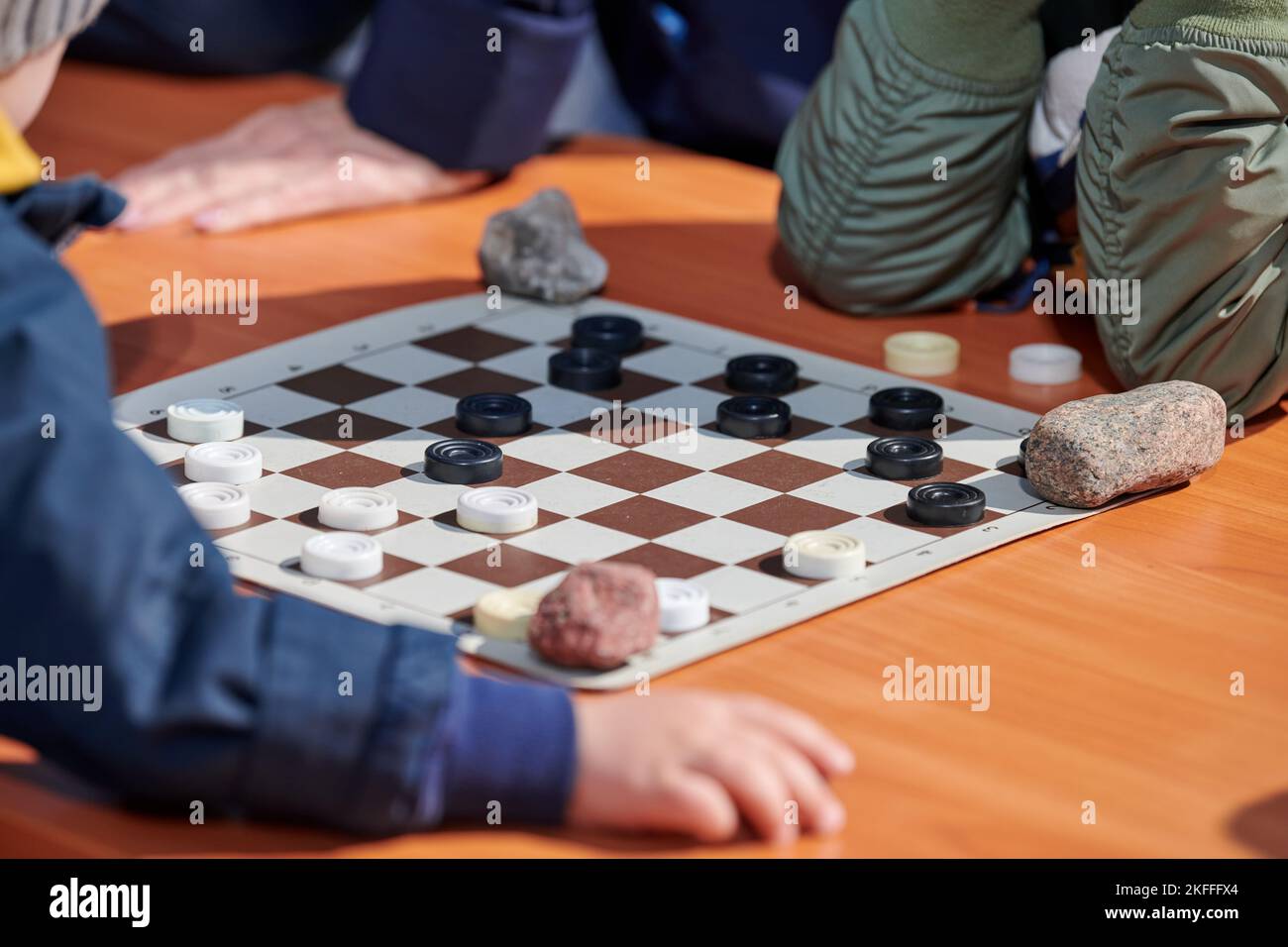Outdoor draughts competition on paper checkerboard on table, close up ...