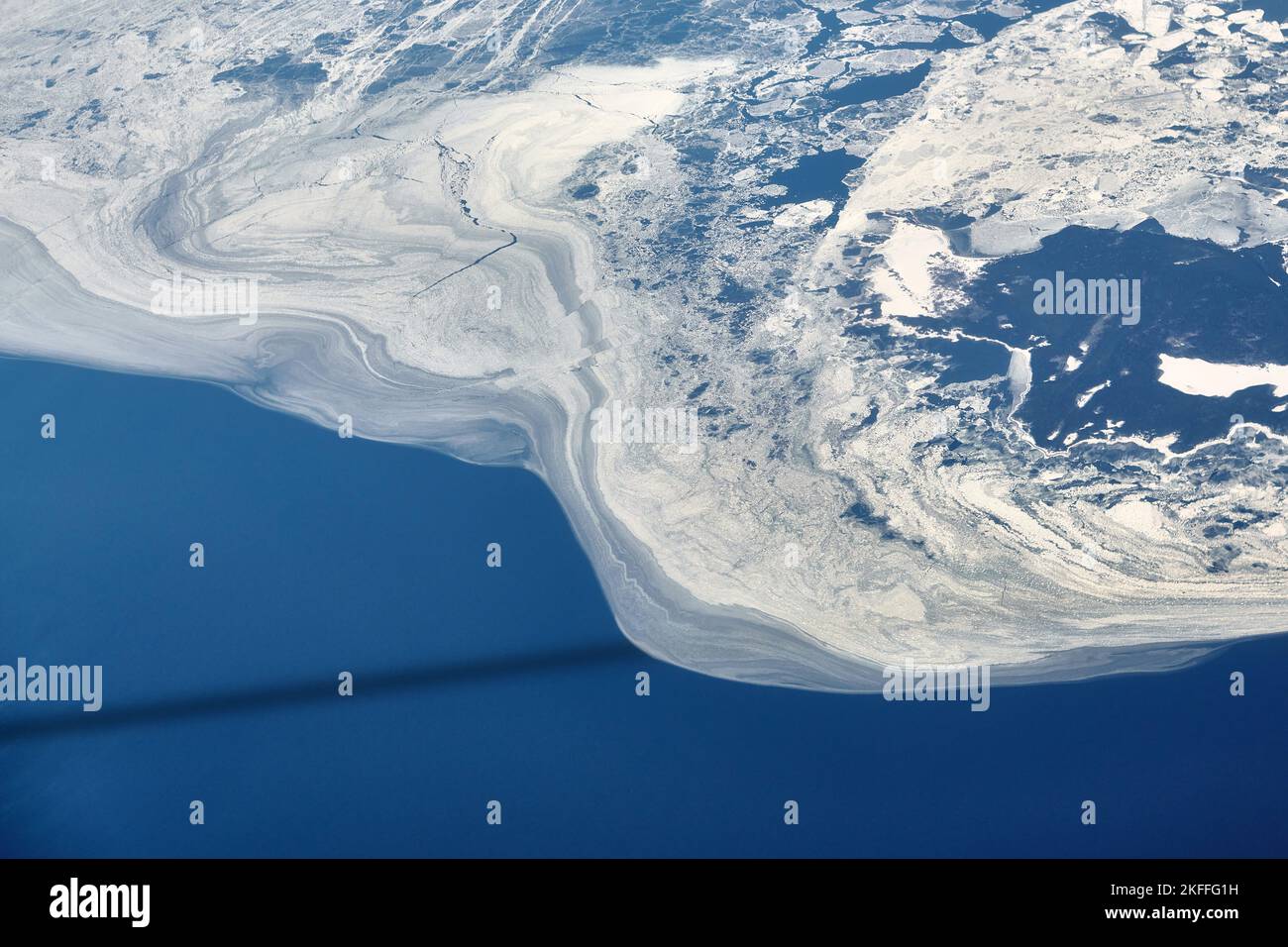 Aerial view from airplane window over clouds to snow covered frozen sea ...