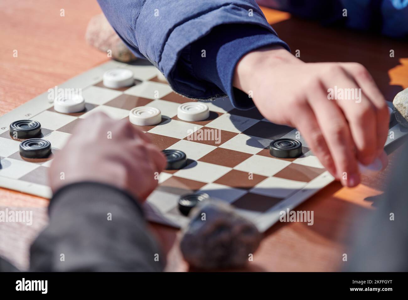 Outdoor draughts competition on paper checkerboard on table, close up ...