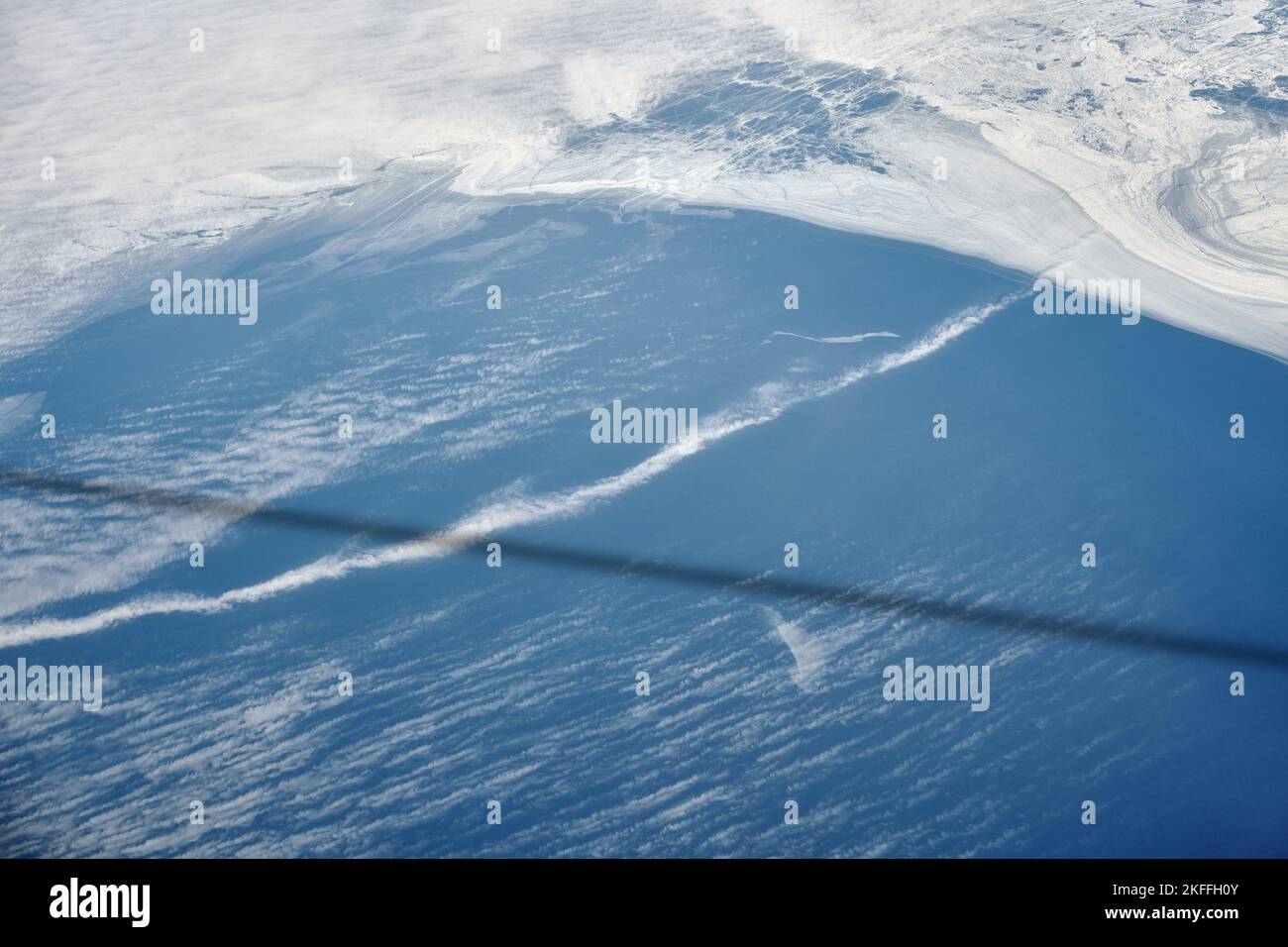 Aerial view from airplane window over clouds to snow covered frozen sea ...