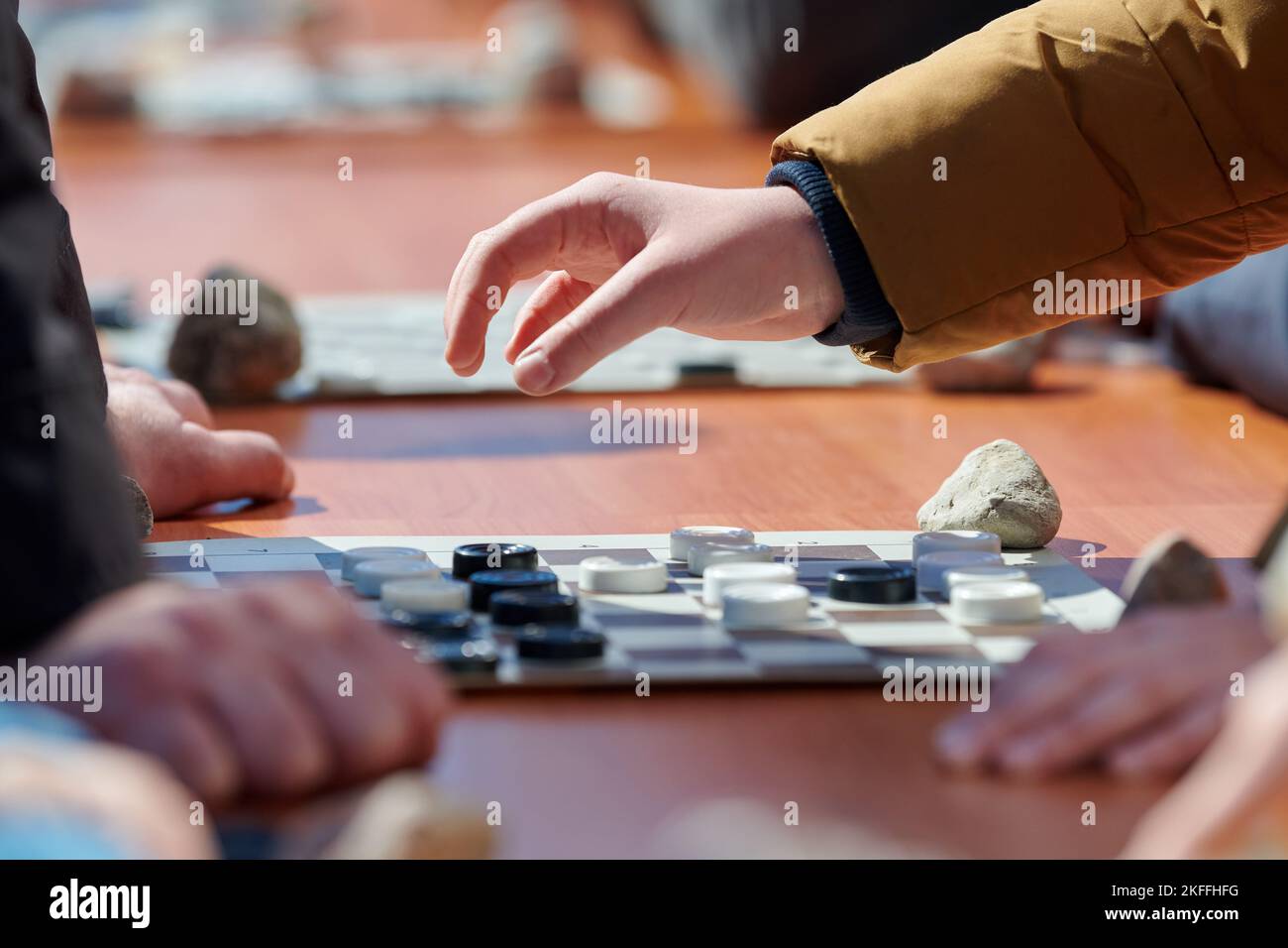 Outdoor draughts competition on paper checkerboard on table, close up ...