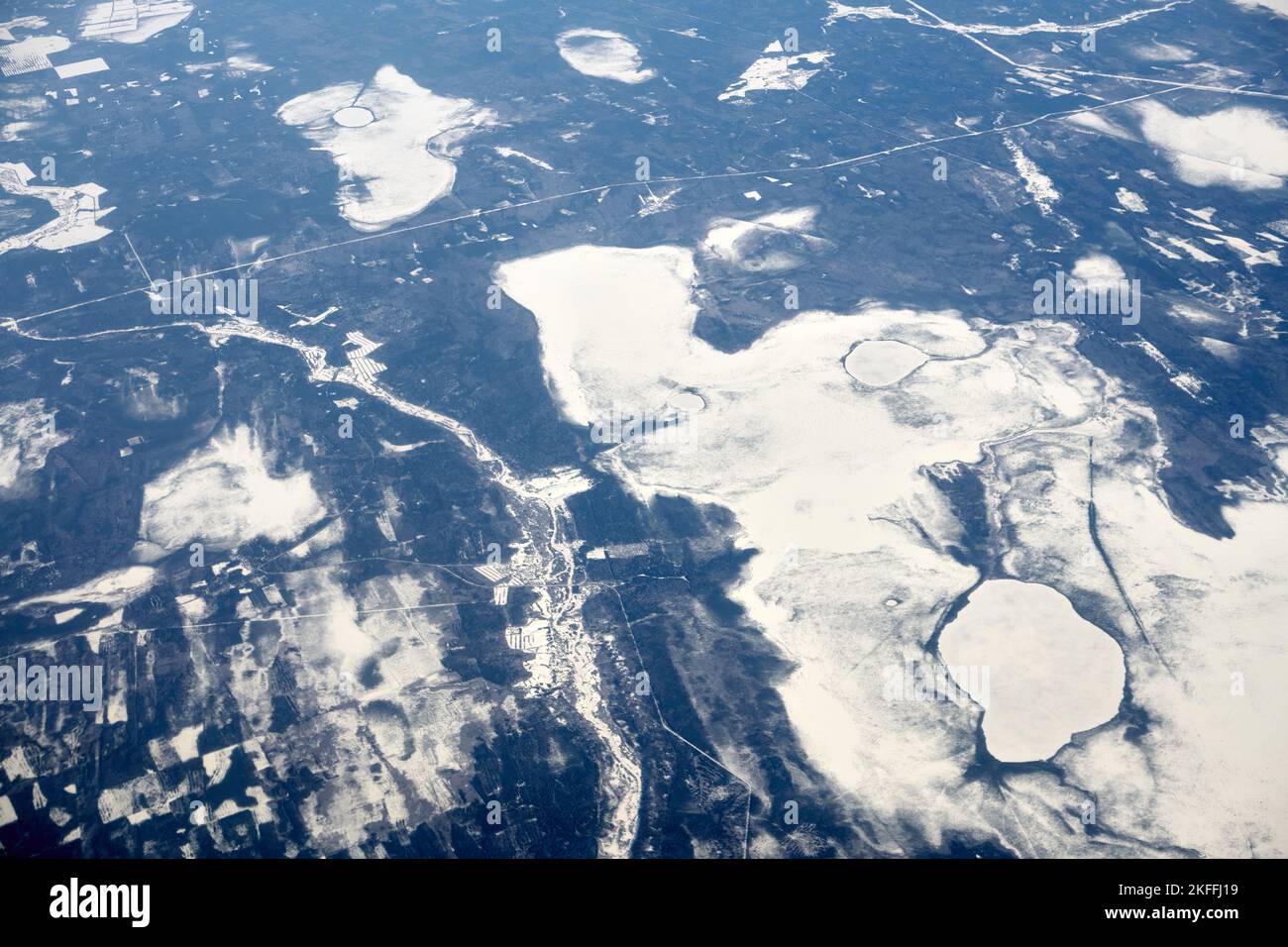 Aerial view from airplane window over clouds top to snow covered rivers ...