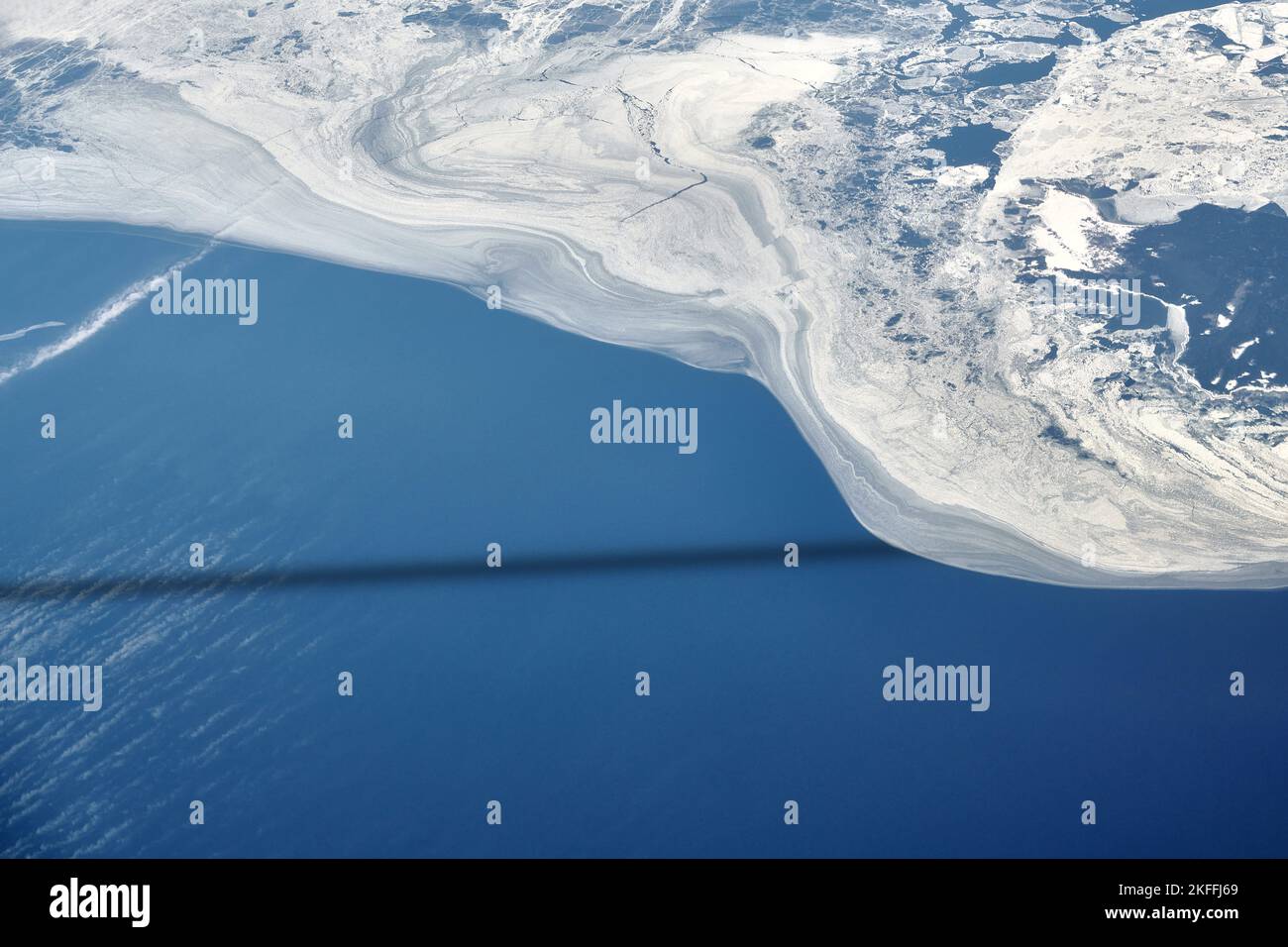 Aerial view from airplane window over clouds to snow covered frozen sea ...
