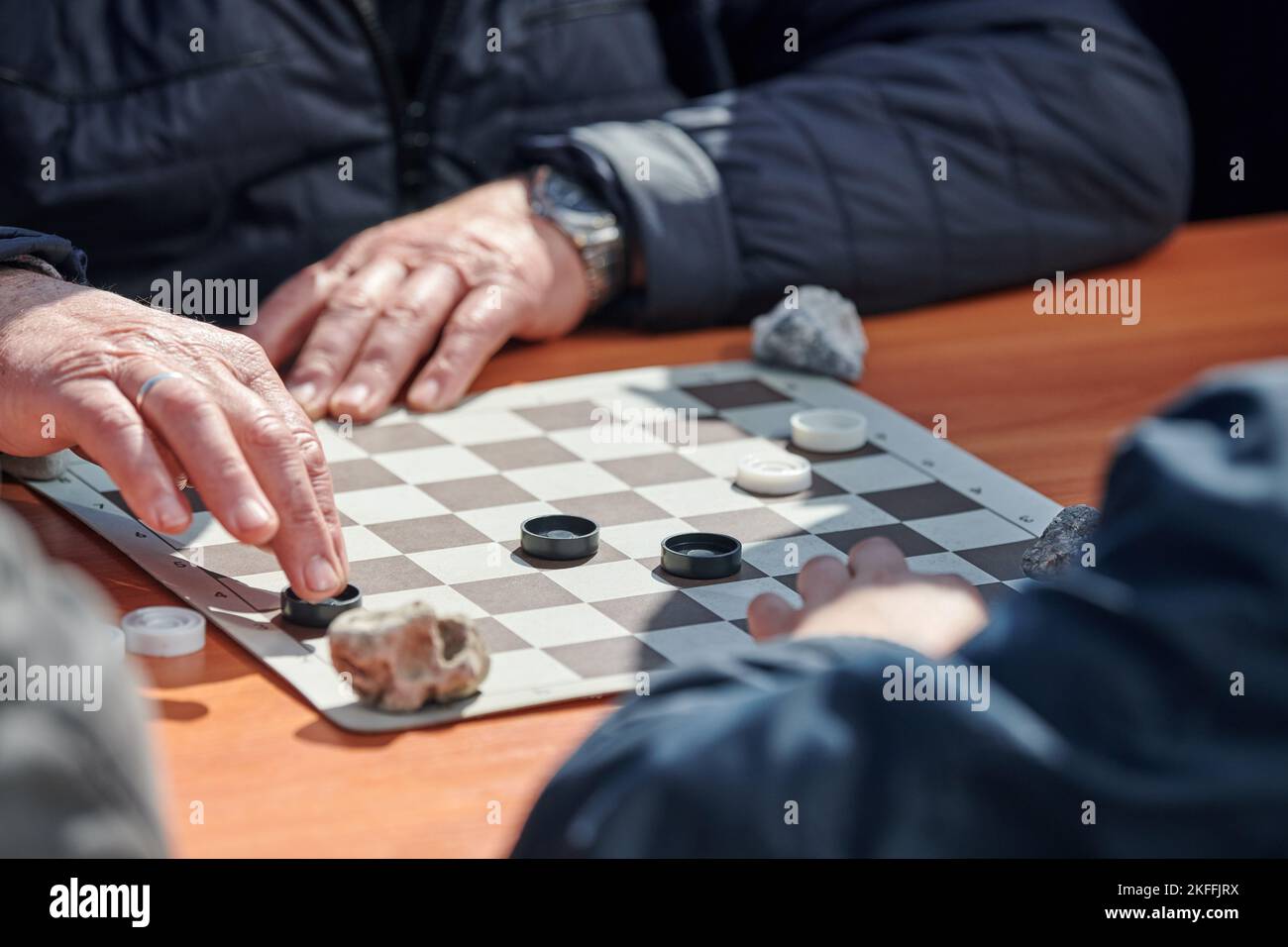 Outdoor draughts competition on paper checkerboard on table, close up ...