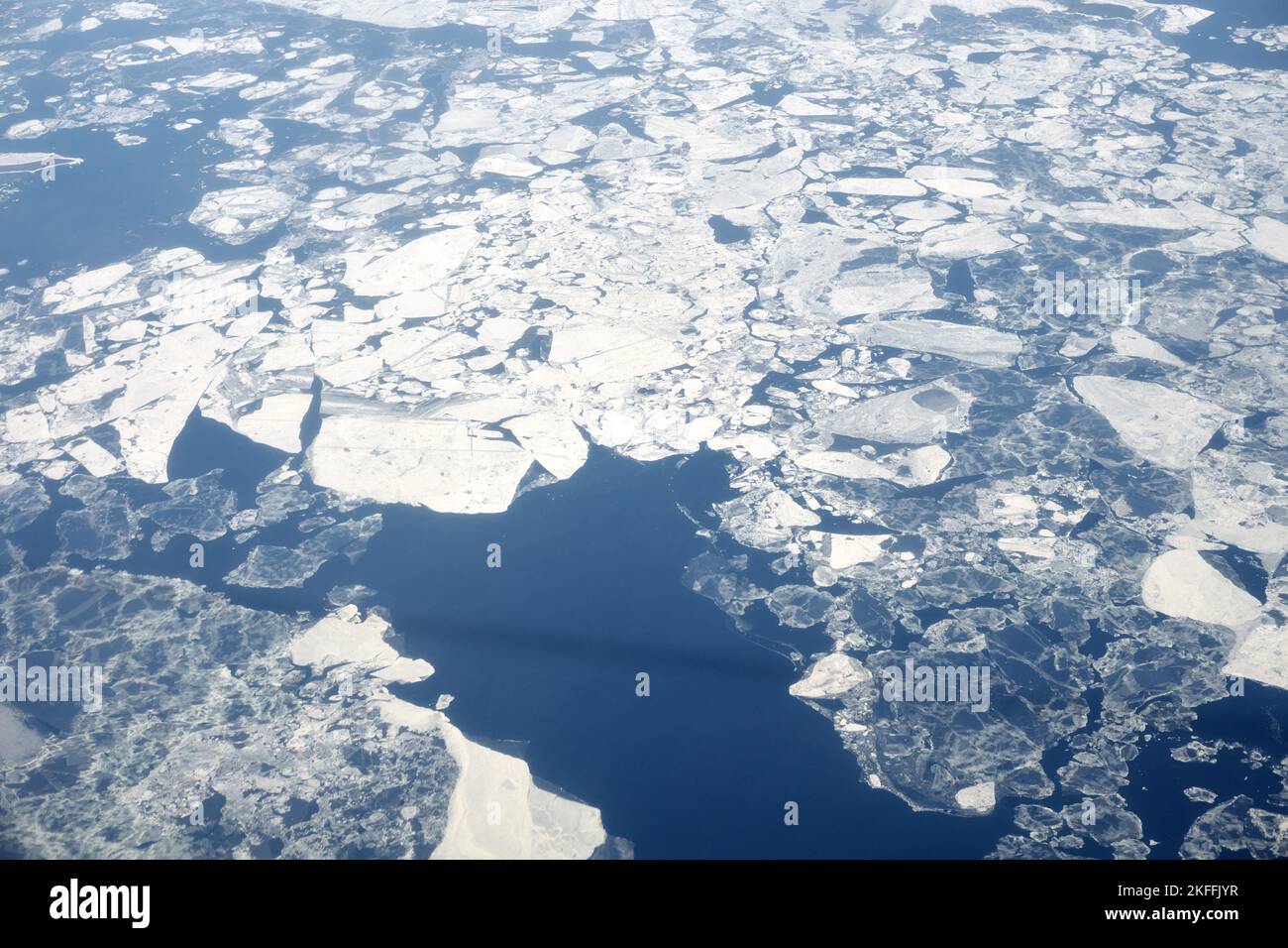 Aerial view from airplane window over clouds to snow covered frozen sea ...
