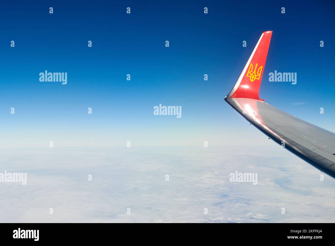 Airplane wing with coat of arms of Ukraine over clouds aerial top view ...