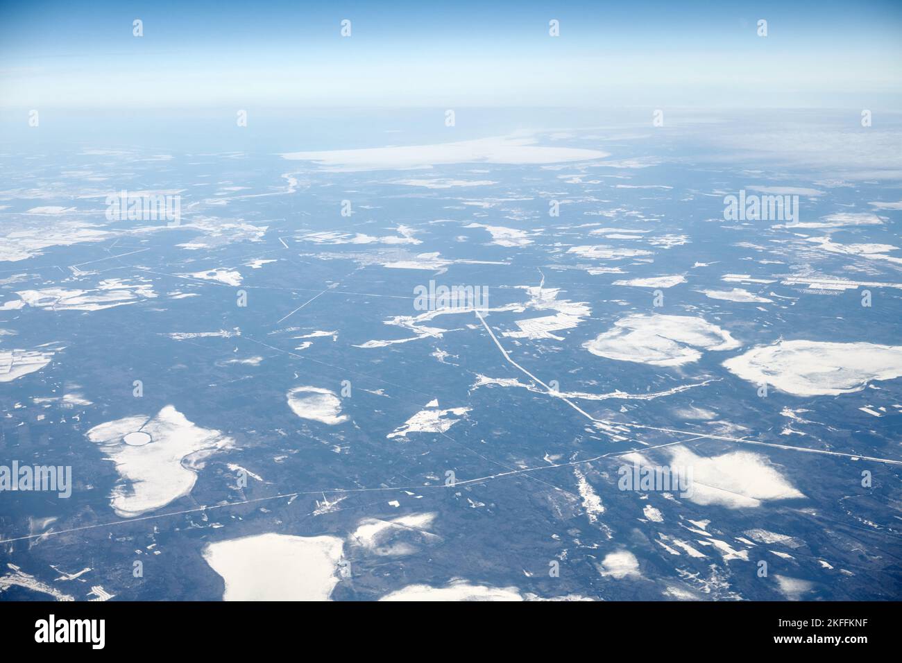 Aerial view from airplane window over clouds top to snow covered rivers ...