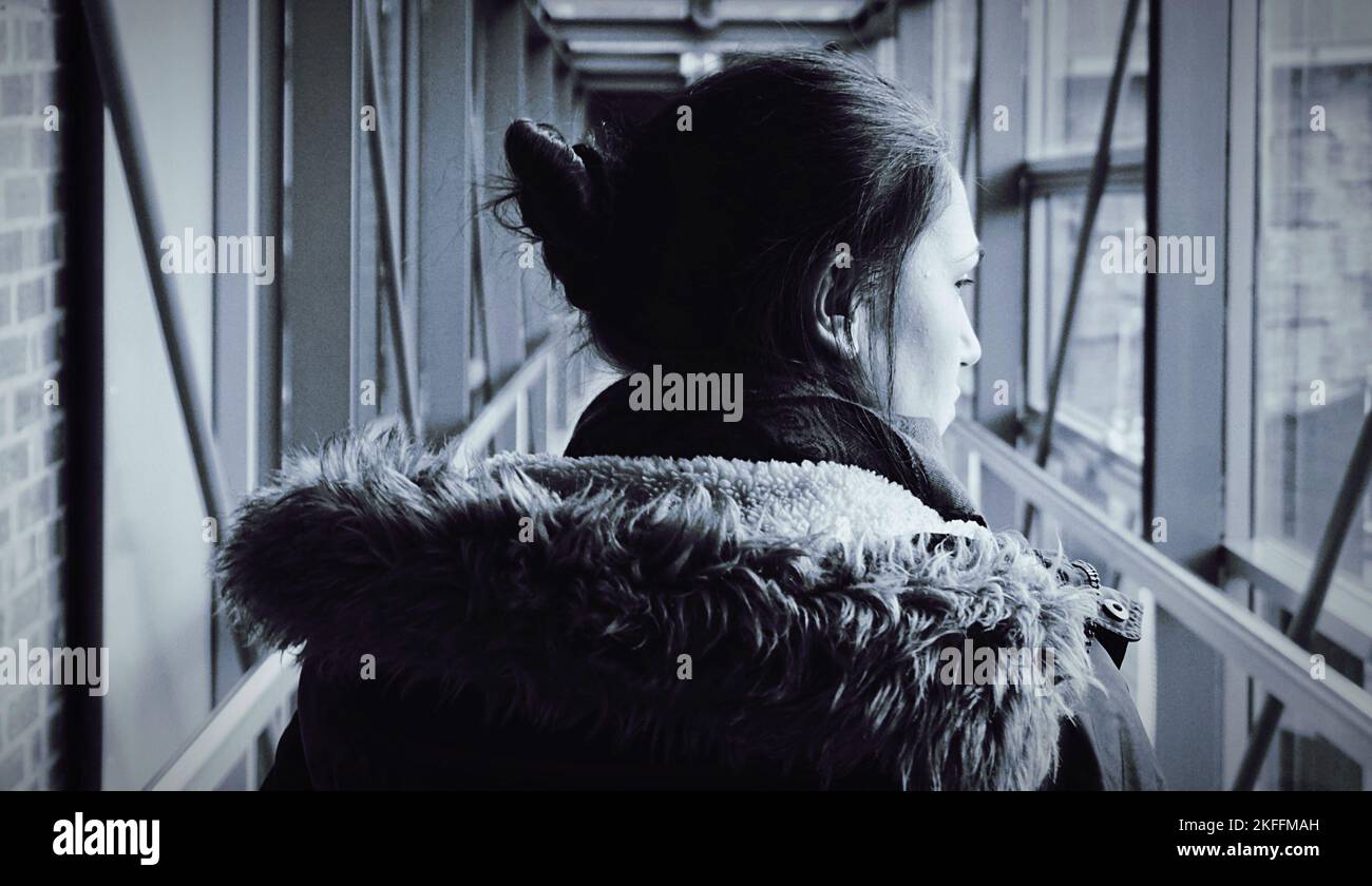 The grayscale portrait of a female walking through a corridor from ...