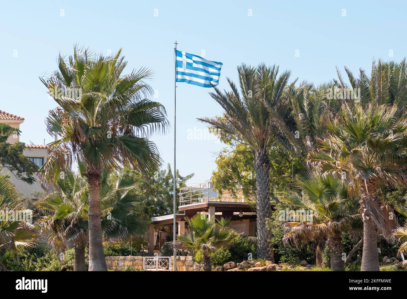 Greek flag waving in the wind surrounded by palm trees and beach ...