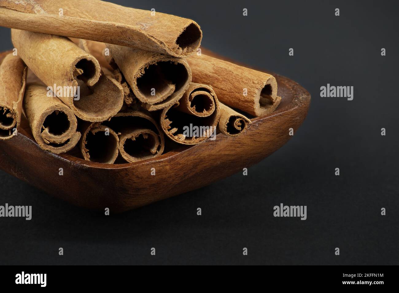 Cinnamon sticks bundle in a wooden plate over black background with ...