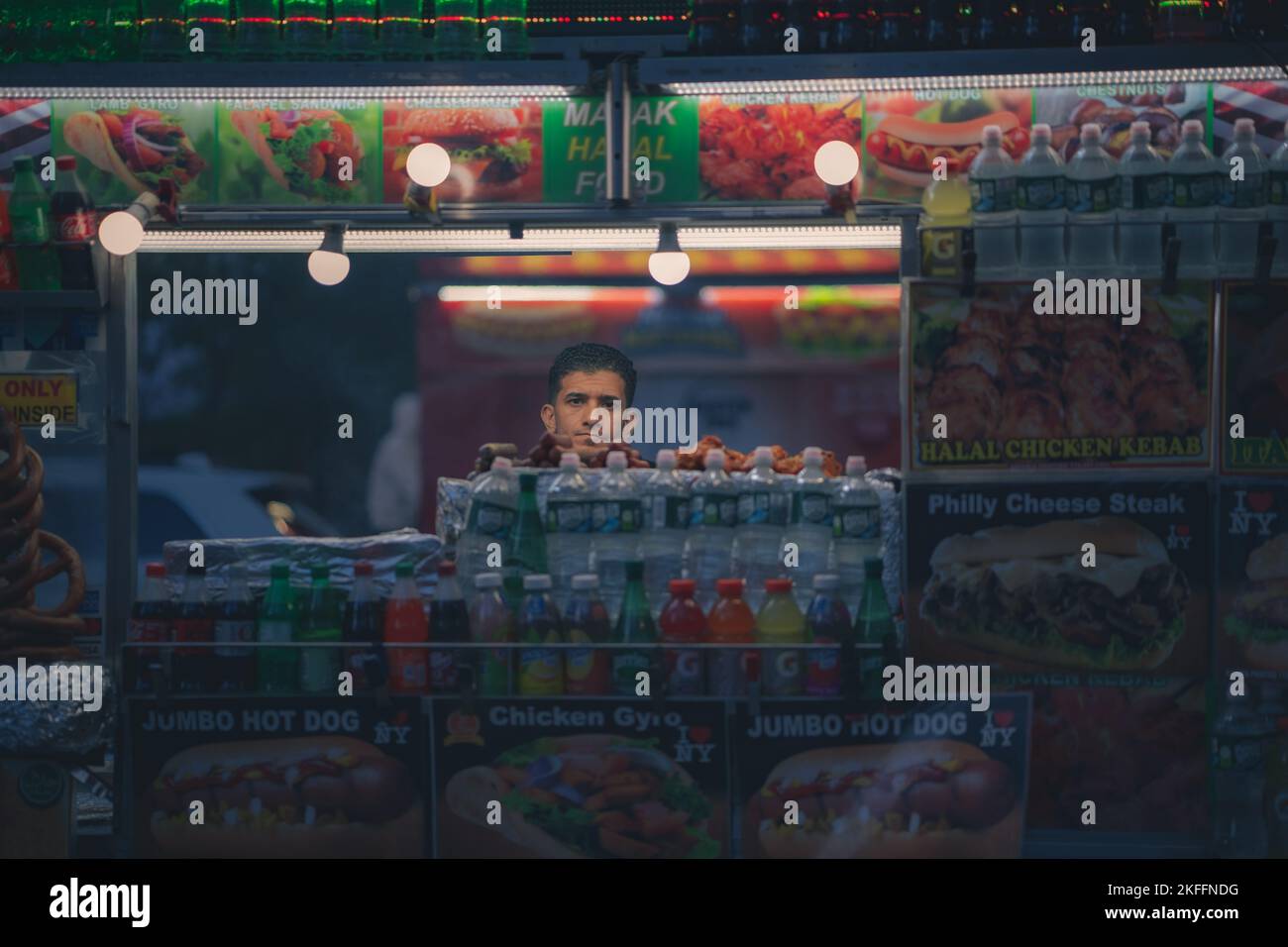 A male vendor behind a drinks stall looking at the camera, New York ...