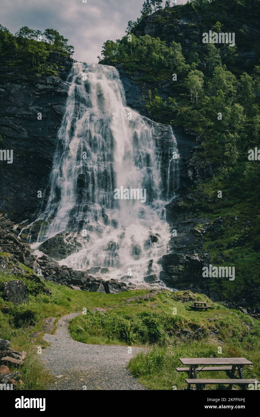 A vertical and long exposure shot of a waterfall in a valley emerging ...
