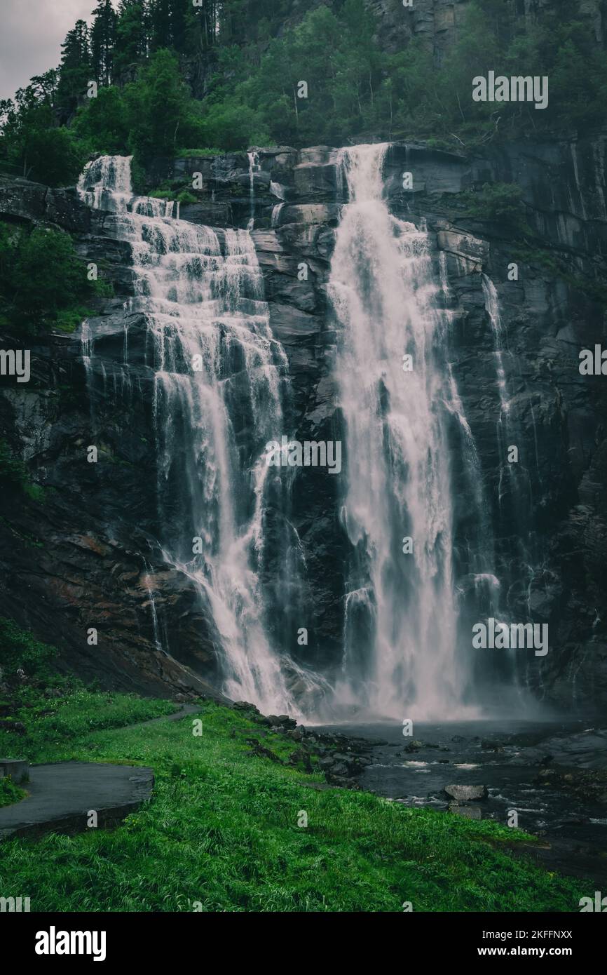 A vertical and long exposure shot of a waterfall in a valley emerging ...