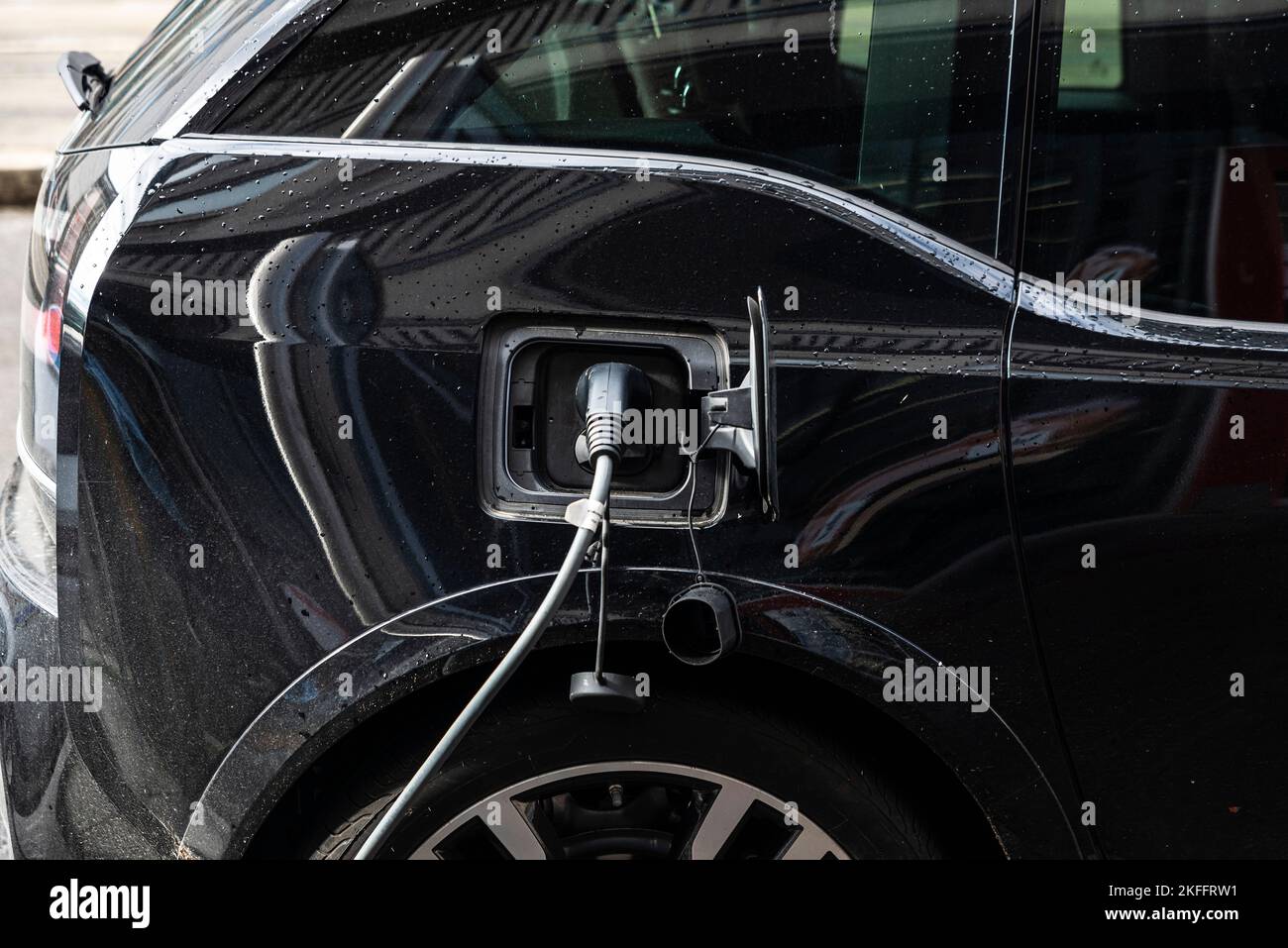 Black electric car recharging batteries at a recharge point station in ...