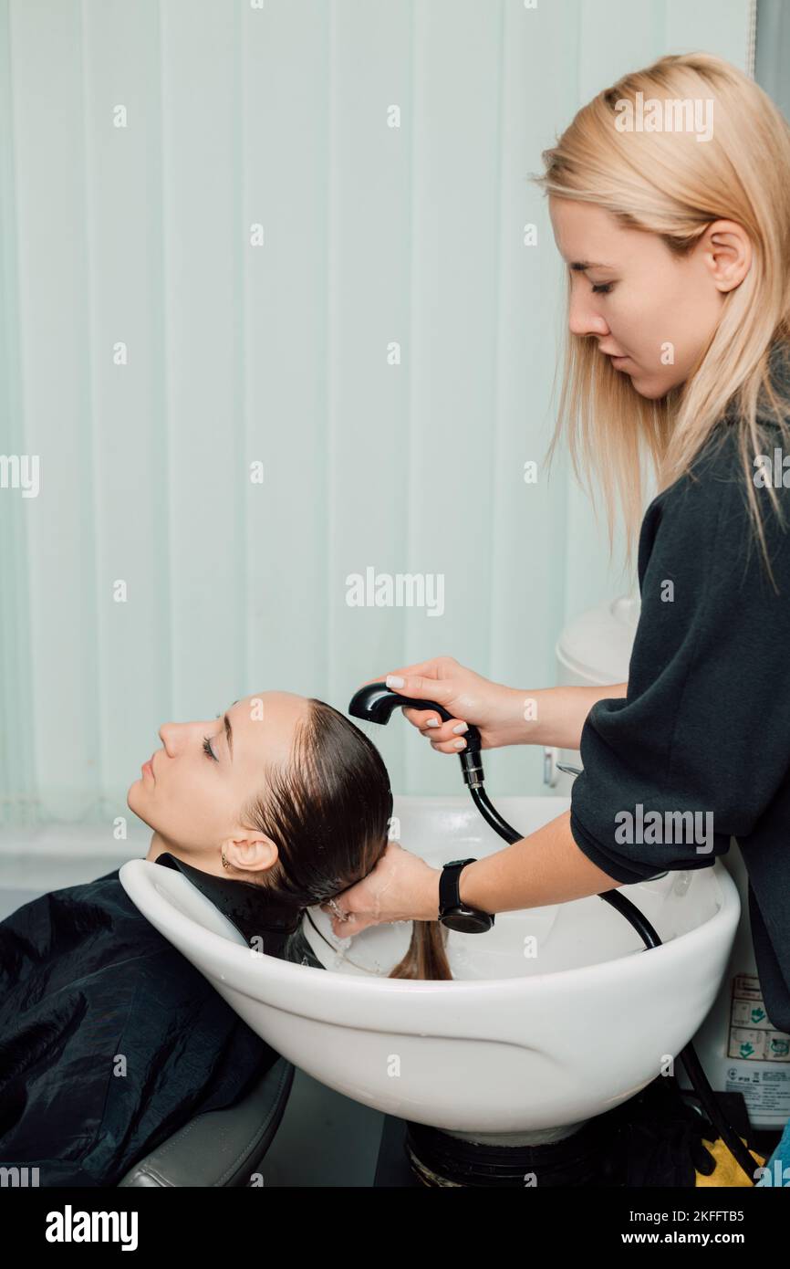 The hairdresser washes the client's hair in the salon. Hair dyeing and ...