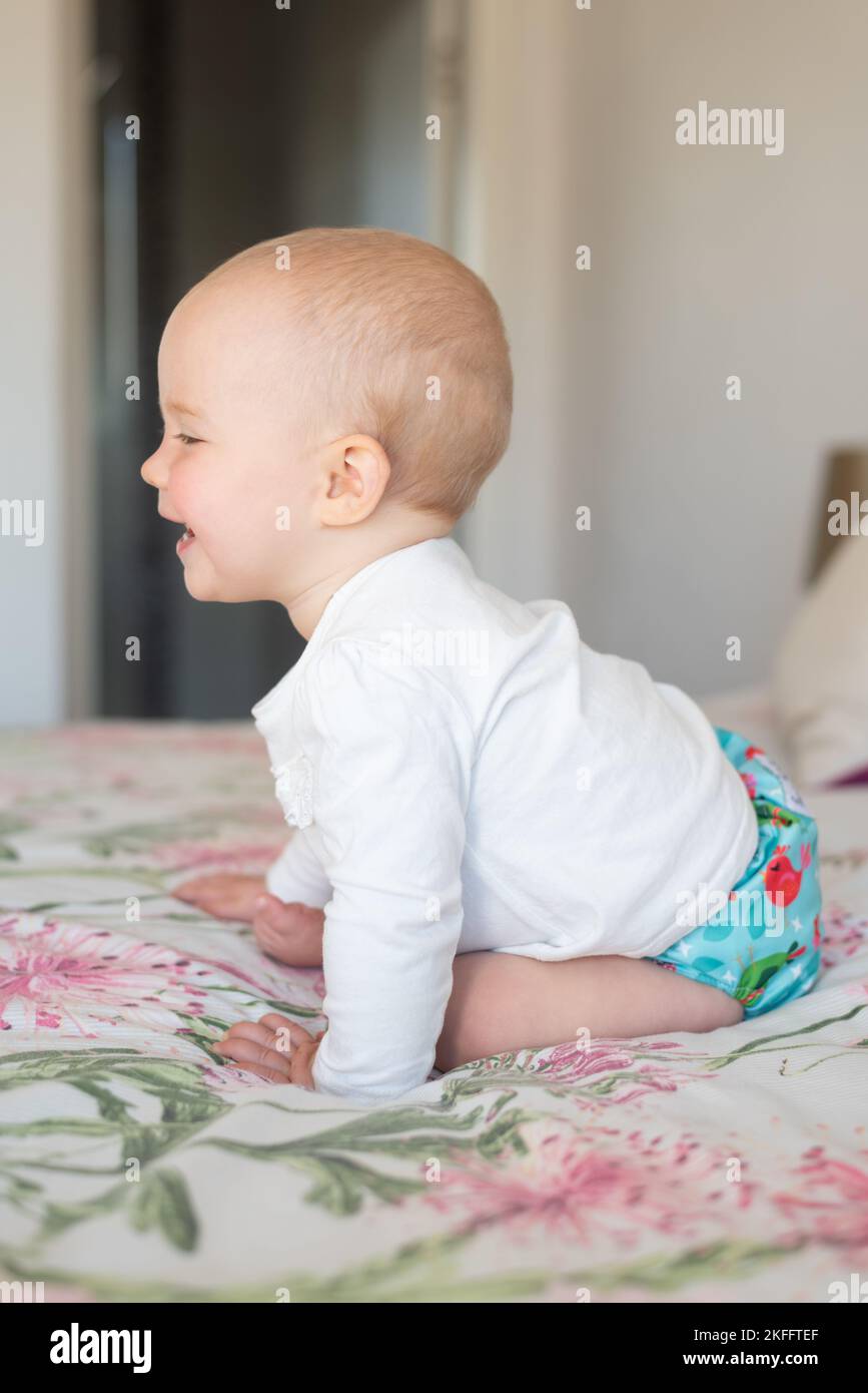 A happy baby girl learning how to sit. She is wearing a modern ...