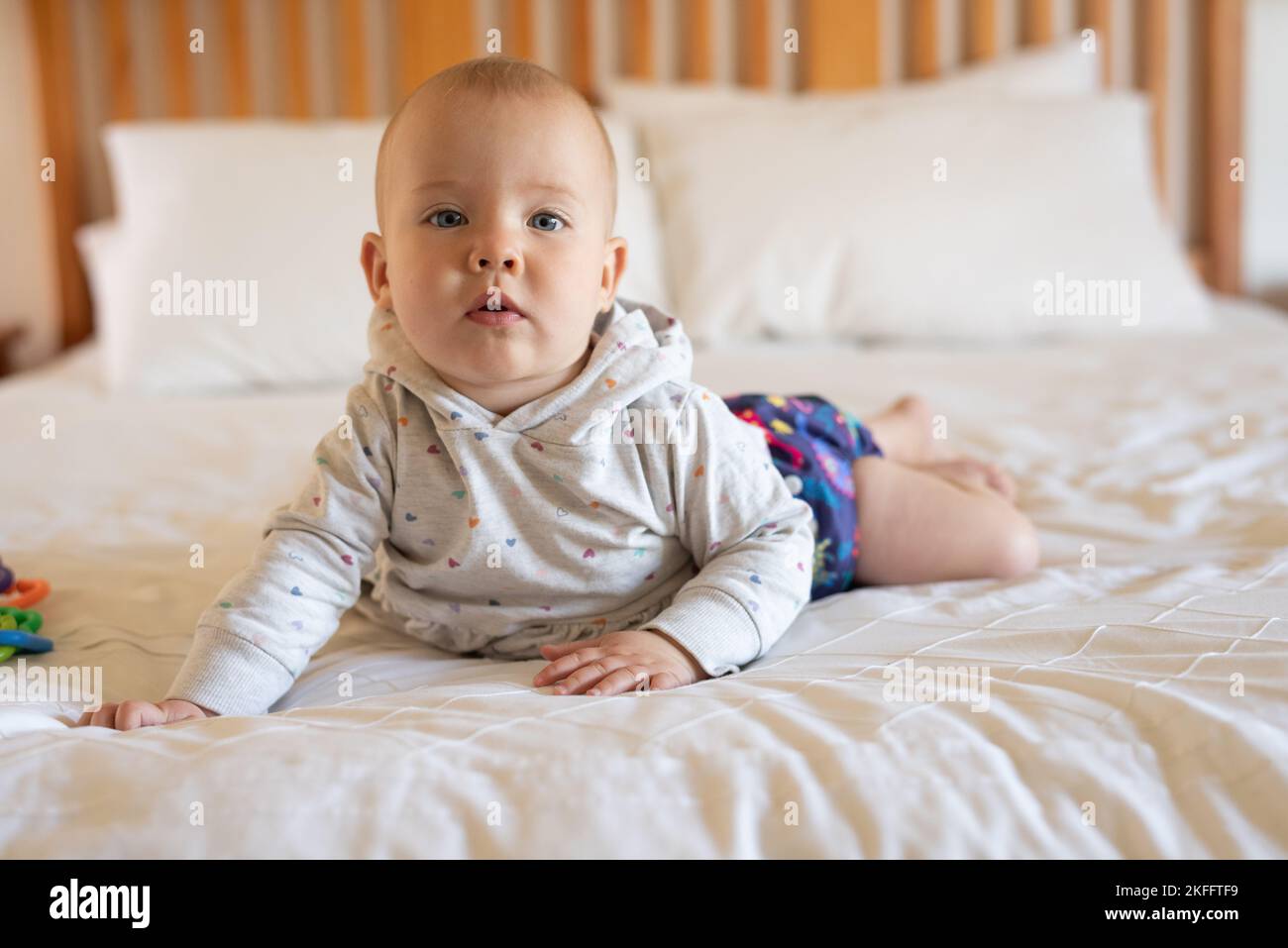 A baby girl lying on her stomach doing tummy time to strengthen her ...