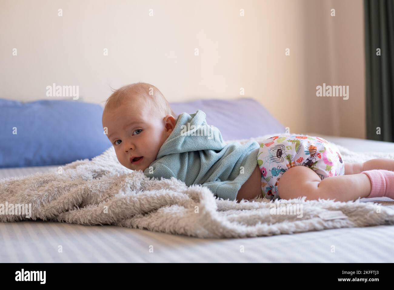 A baby girl lying on her stomach doing tummy time to strengthen her ...