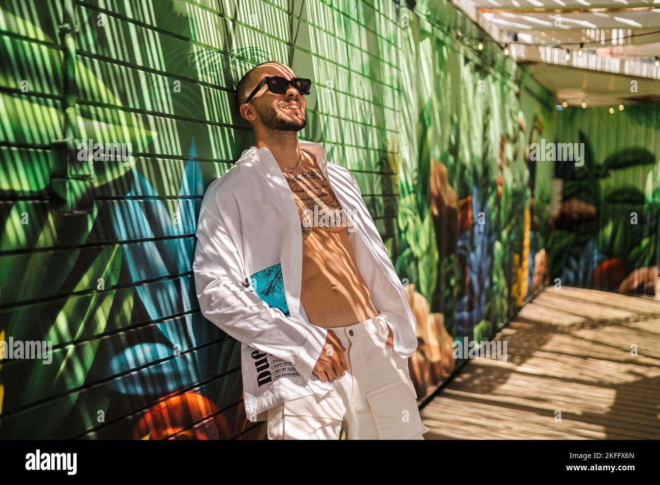 A view of the young, Spanish man posing with palm tree shadows on him ...