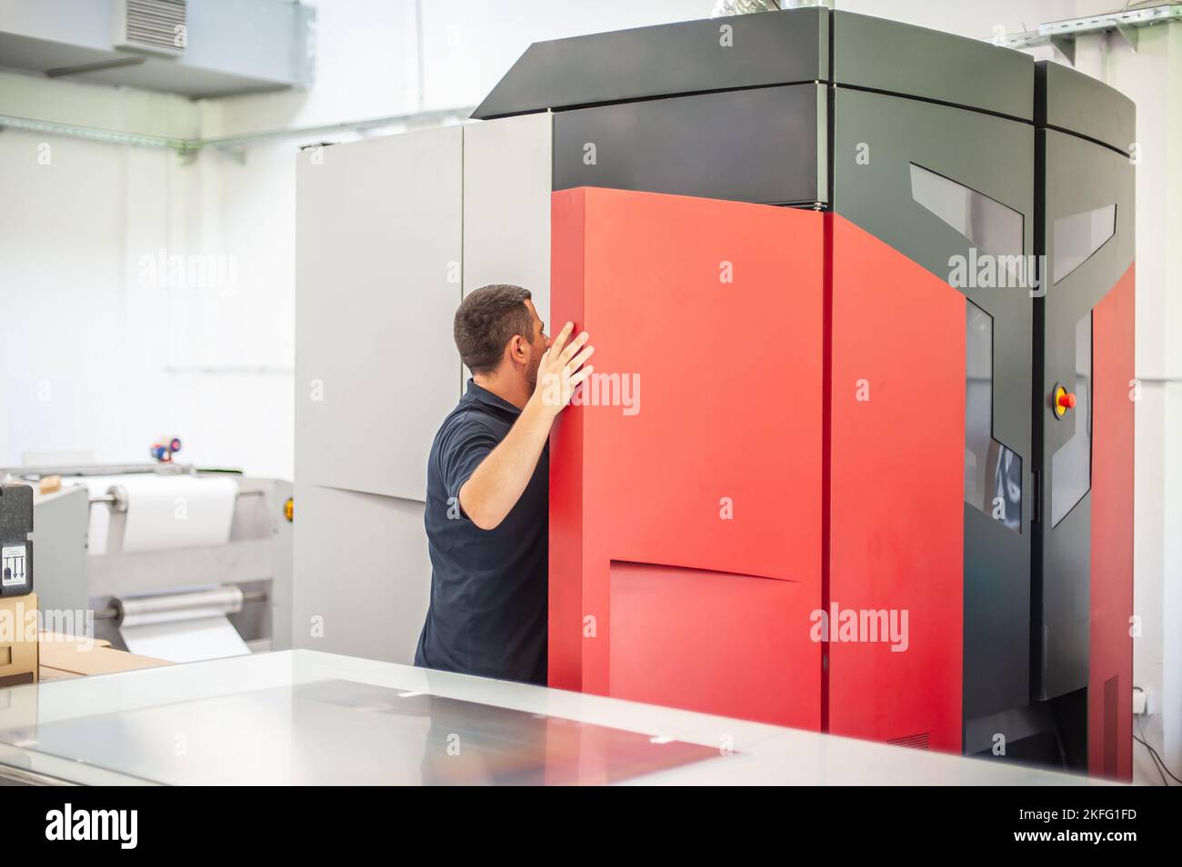 Professional worker with modern big offset printing machine in print ...