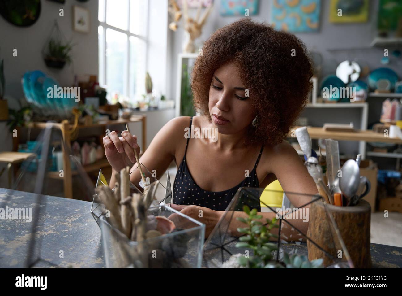 Focused brunette lady creating a florarium at professional studio Stock ...