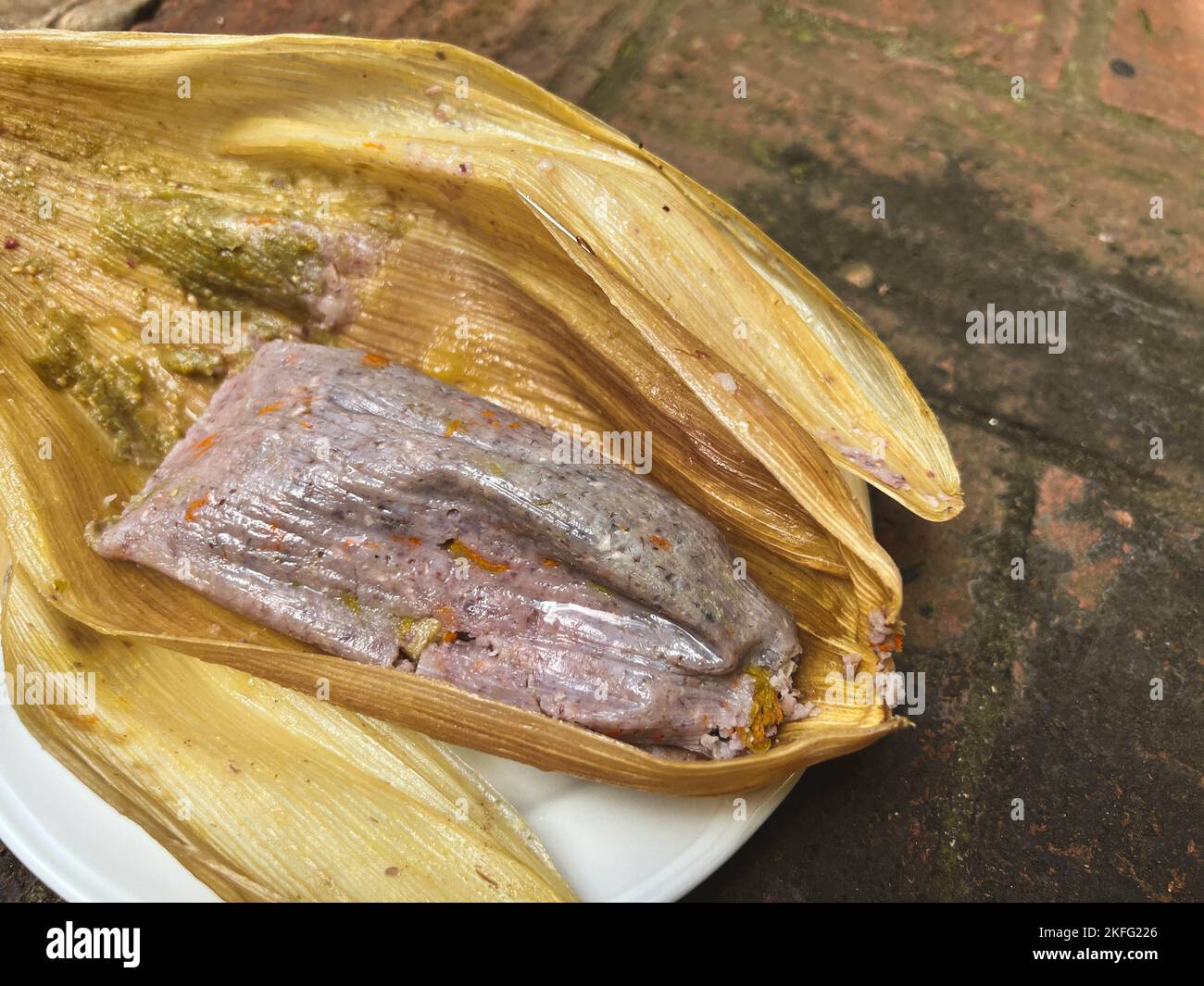 Tamale made from blue corn with squash blossoms wrapped in a corn husk ...