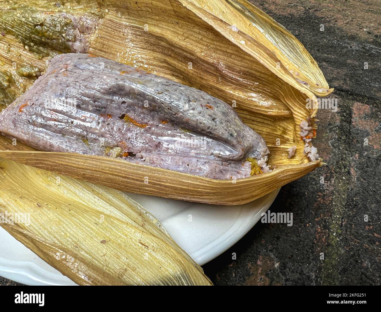 Tamale made from blue corn with squash blossoms wrapped in a corn husk ...