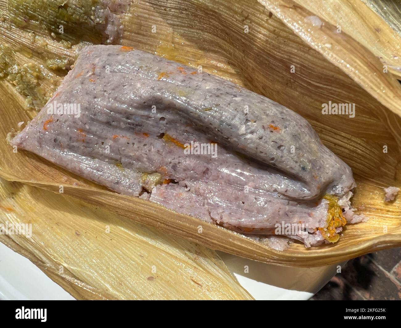 Tamale made from blue corn with squash blossoms wrapped in a corn husk ...