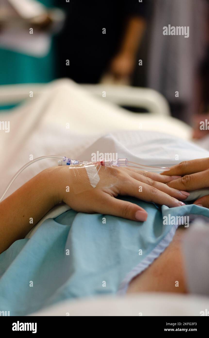 patient in hospital bed with an IV line in her hand waiting for surgery ...