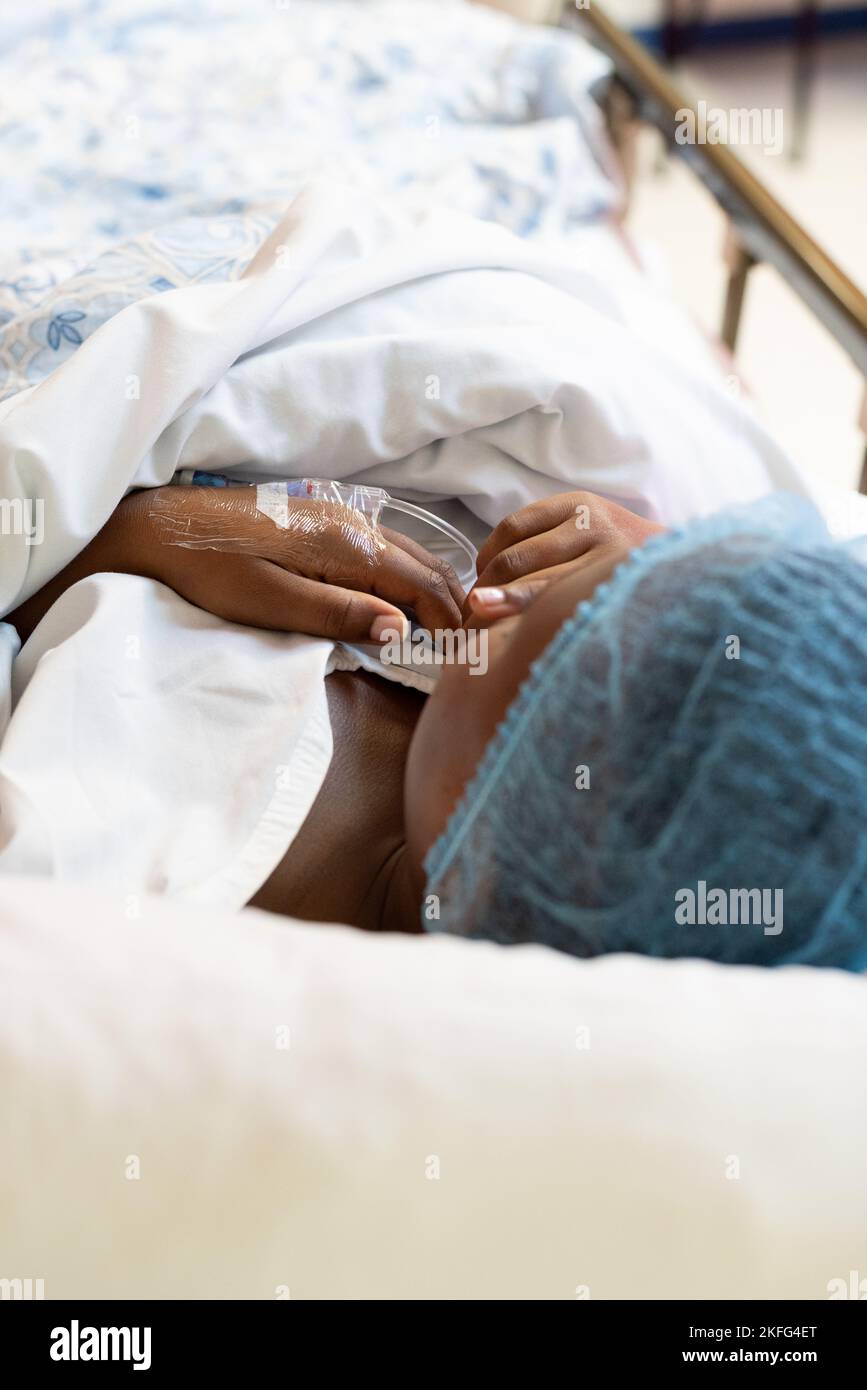 A patient in hospital bed with an IV line in her hand, waiting for ...